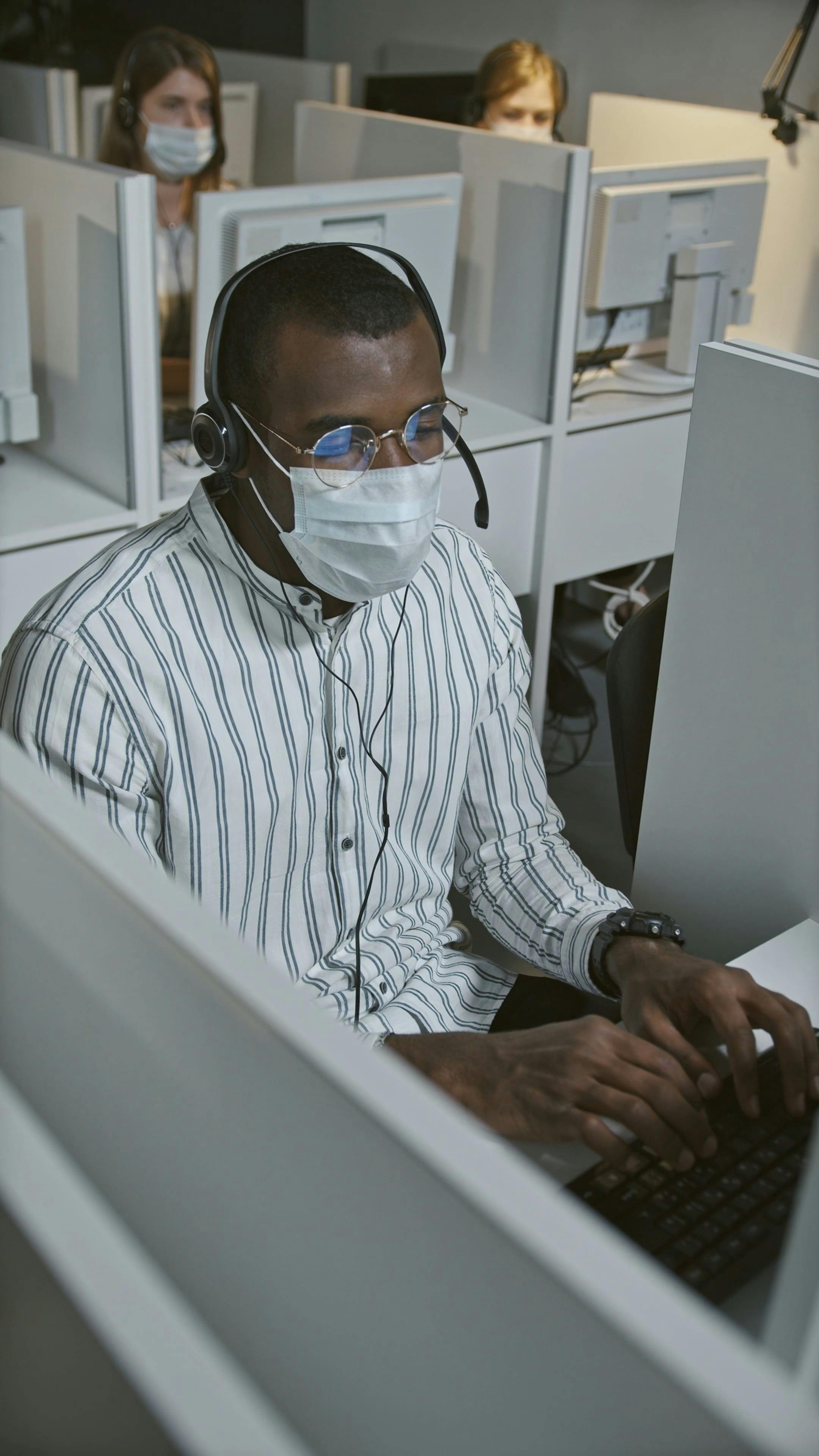 Young Man with Face Mask Working at Call Center · Free Stock Video