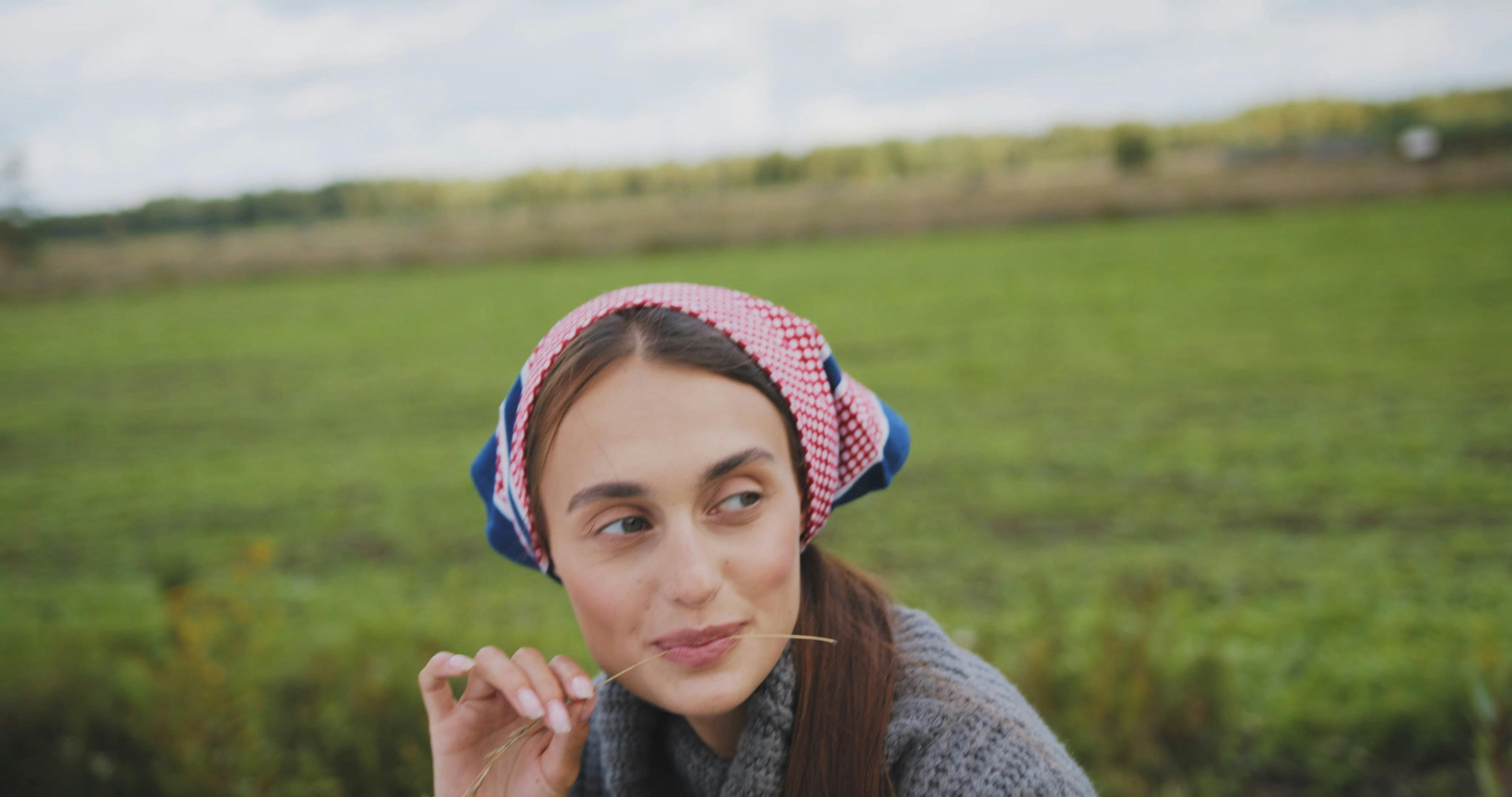 A Woman in a Headscarf Biting on a Piece of Straw Free Stock Video ...