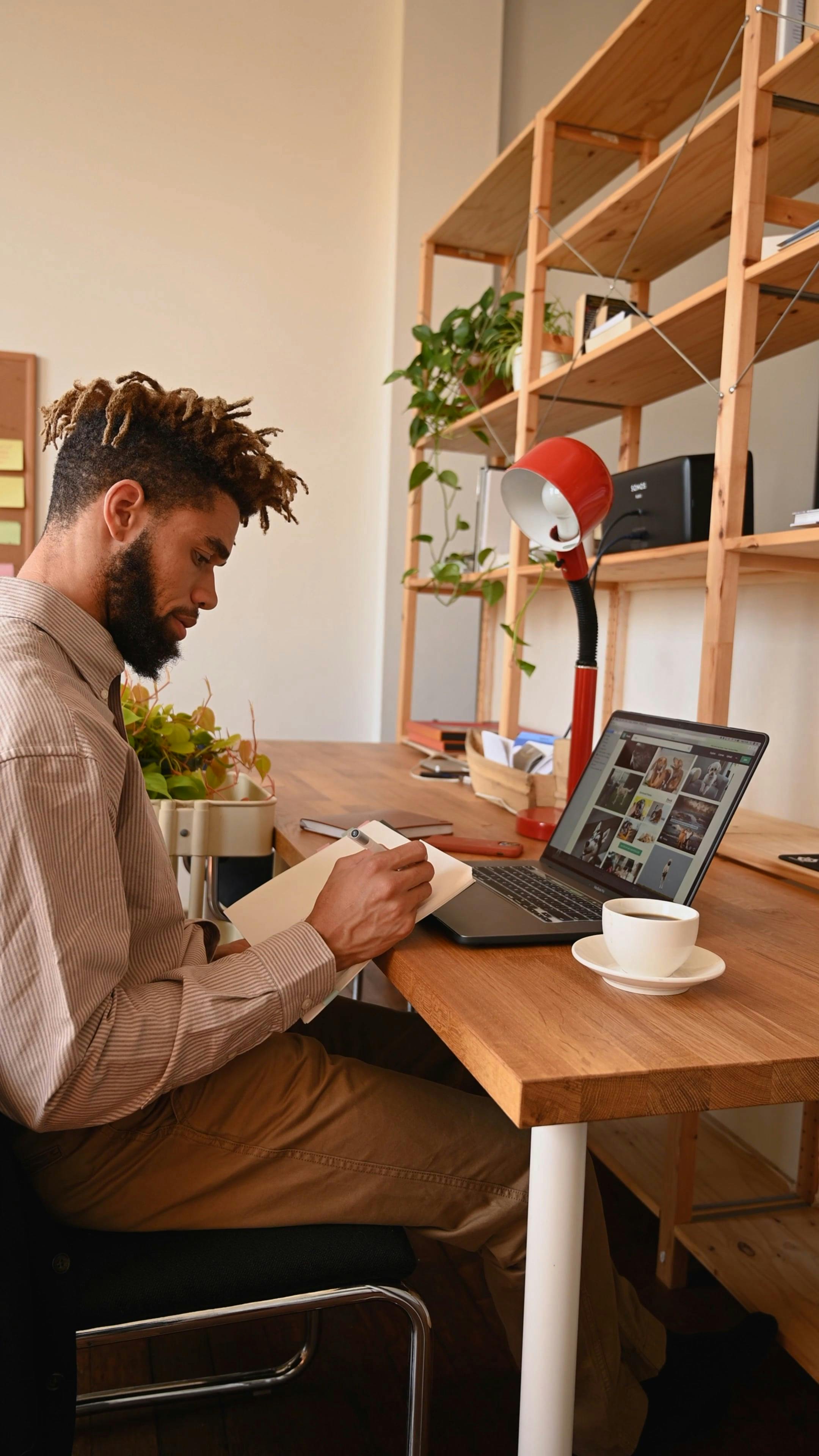 Man with Laptop Writing in a Notebook · Free Stock Video