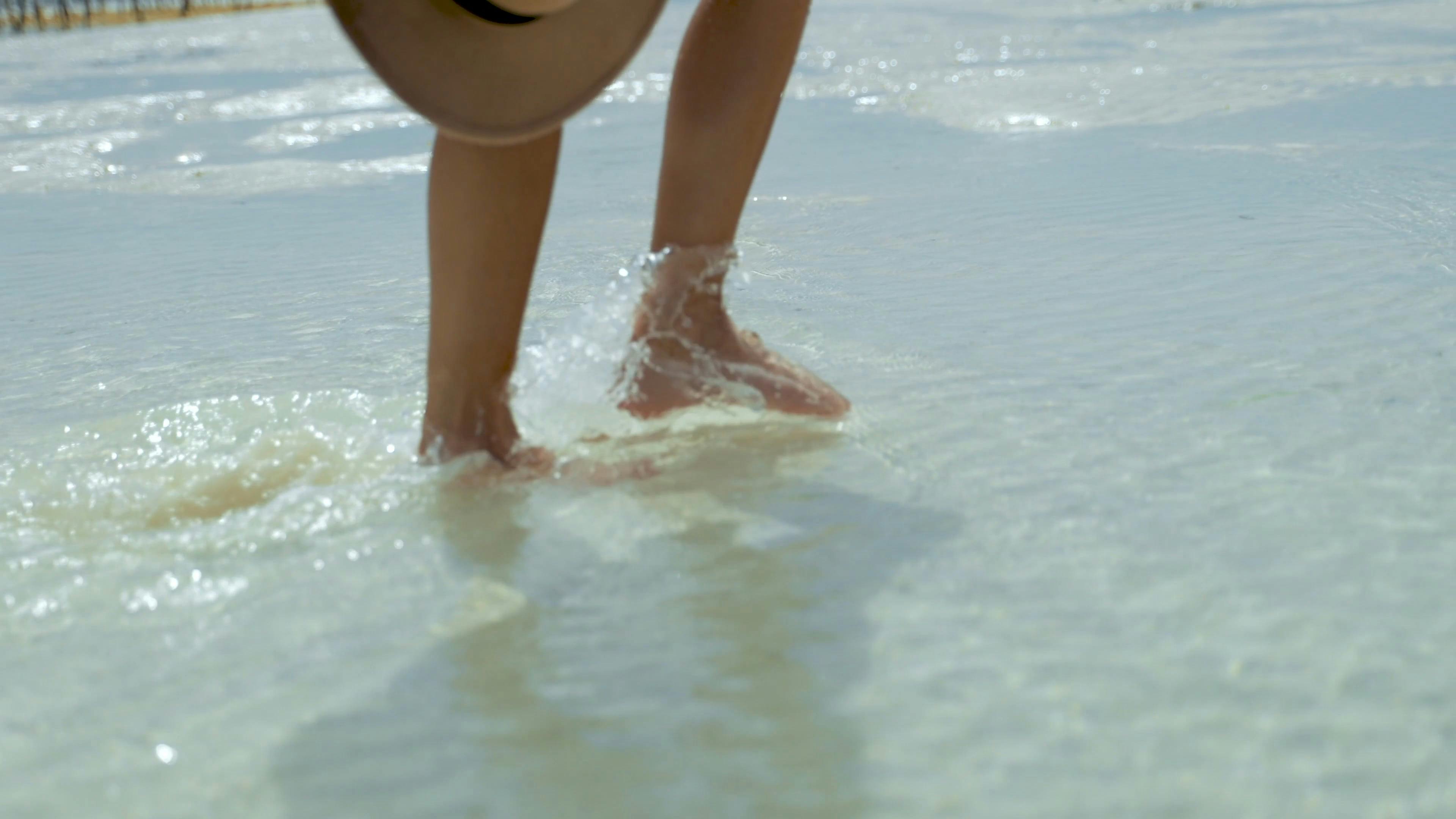 Close Up View of a Person Walking Along the Beach while Holding a Hat ...