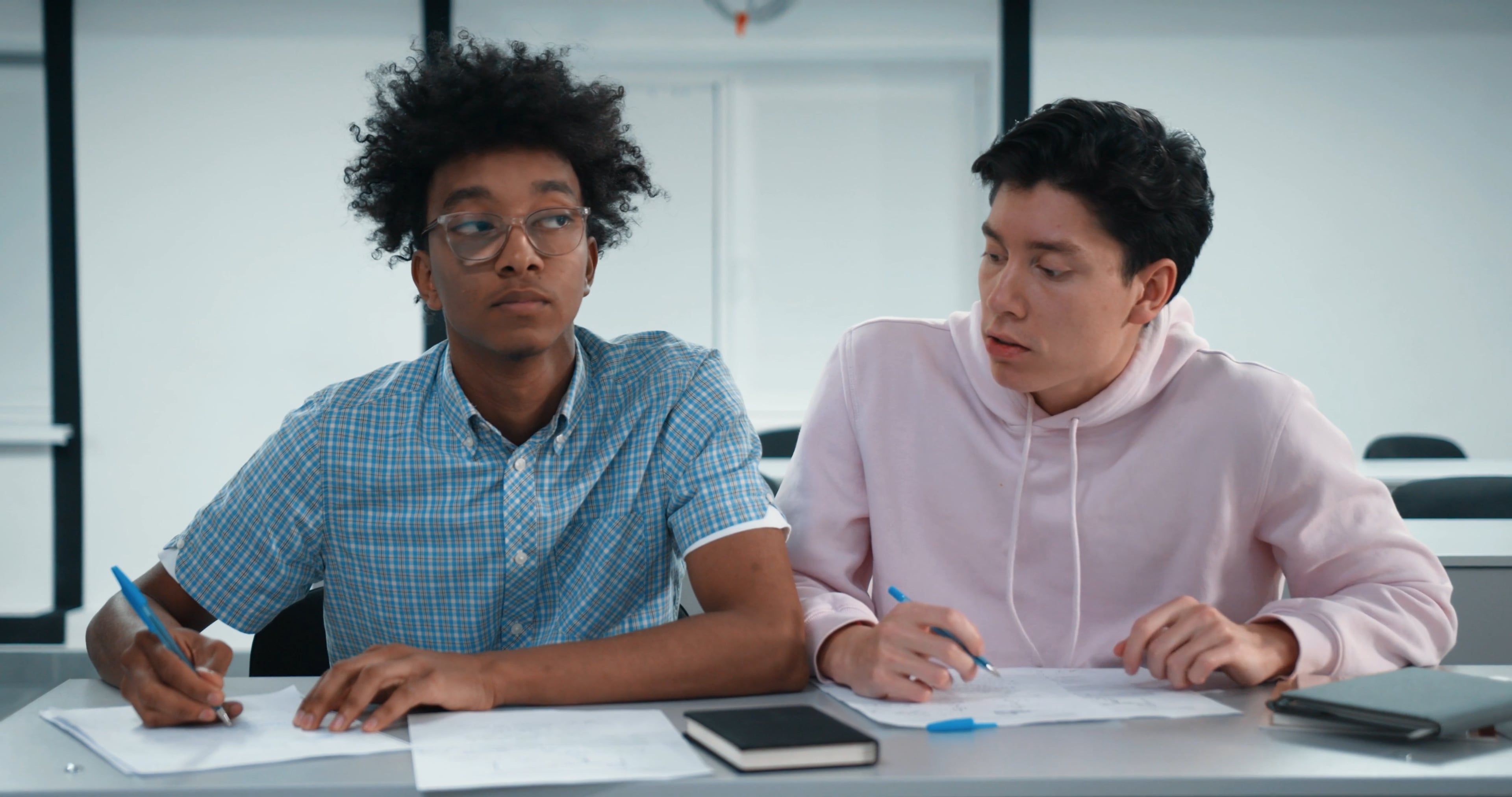 Male Student Answering His Quiz While His Male Seatmate is Trying to ...