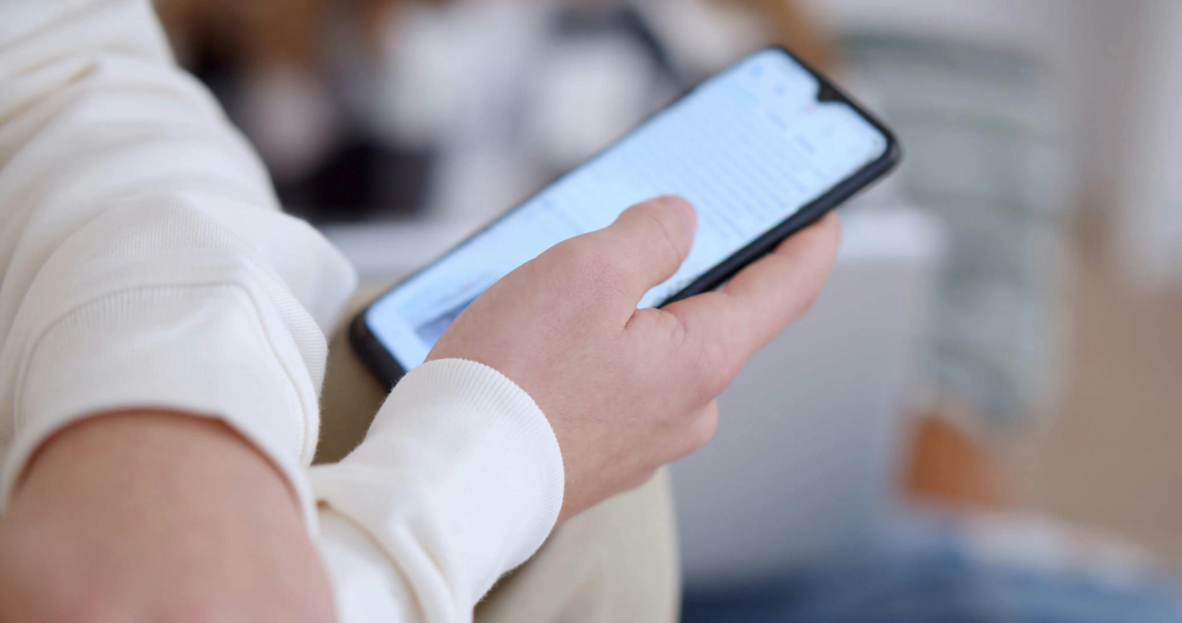 A Person Scrolling Through a Mobile Phone · Free Stock Video