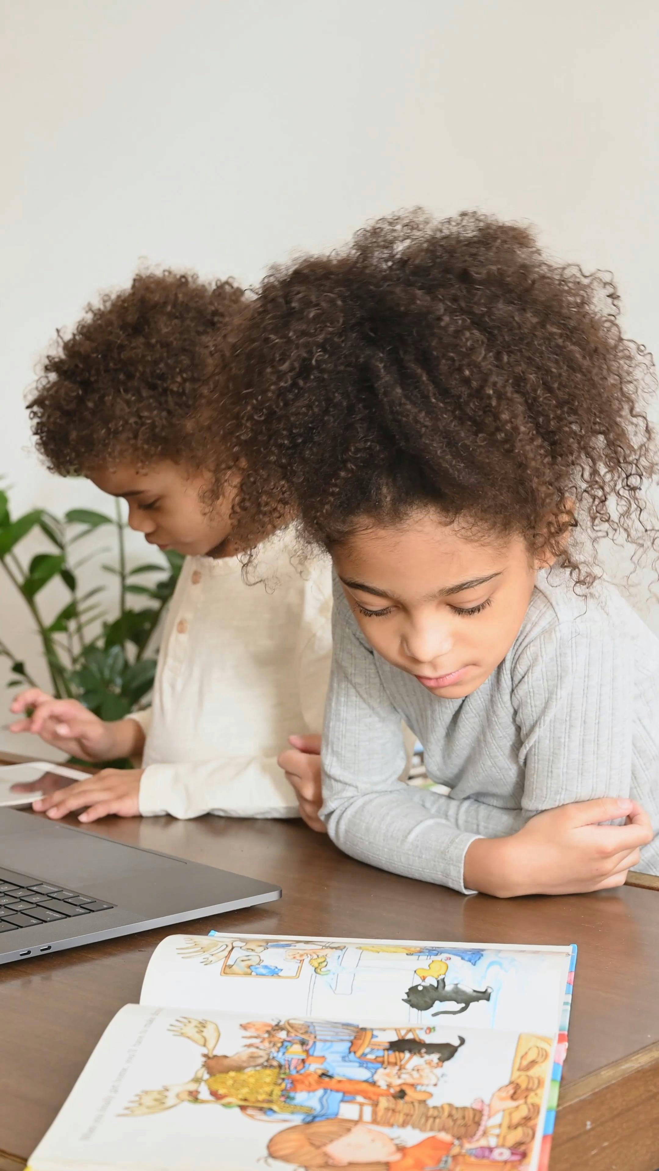 A Boy Tapping on the Tablet While a Girl is Looking at the Laptop ...