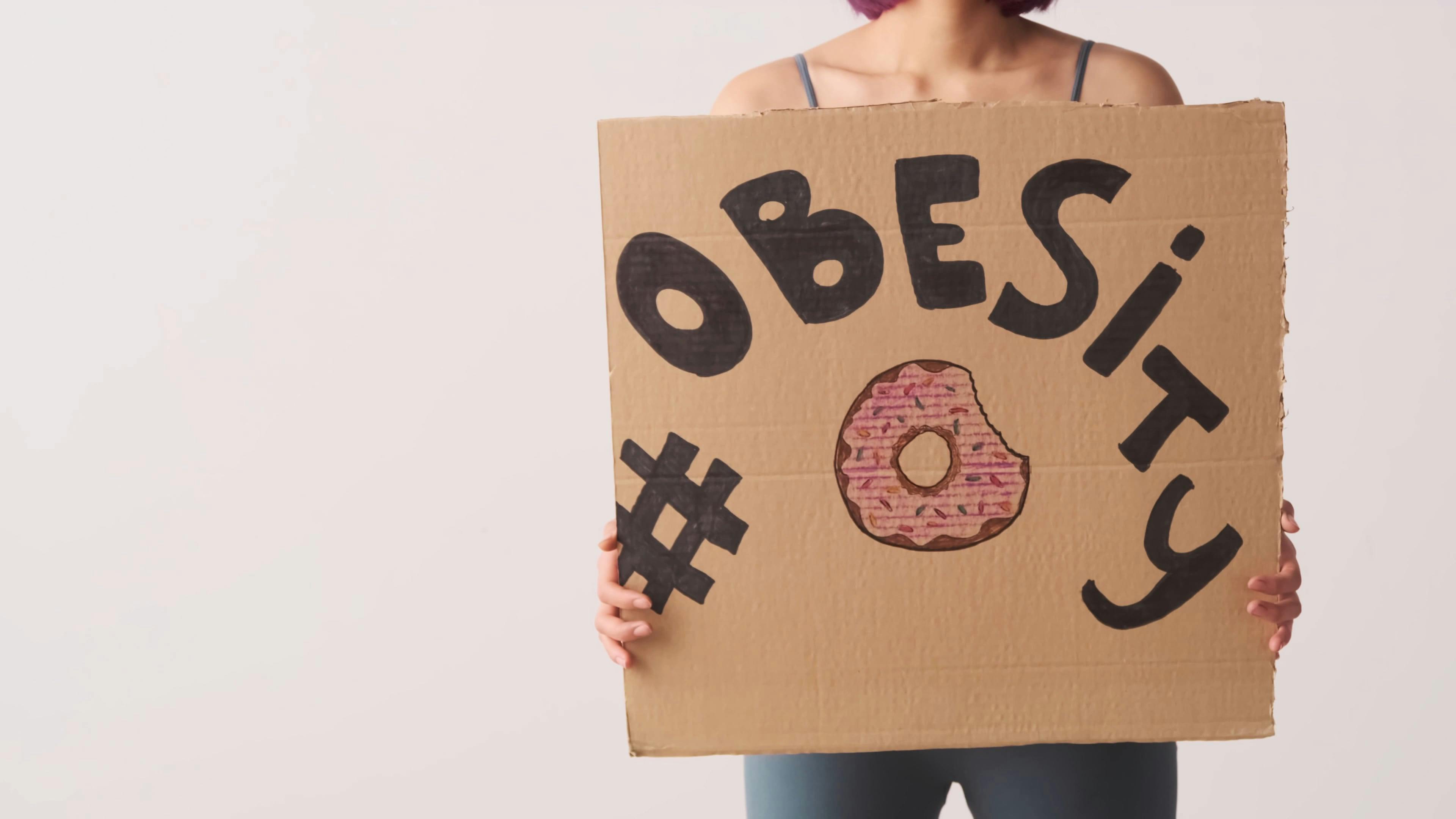 Person Holding a Cardboard with Written Obesity and a Drawing of a ...