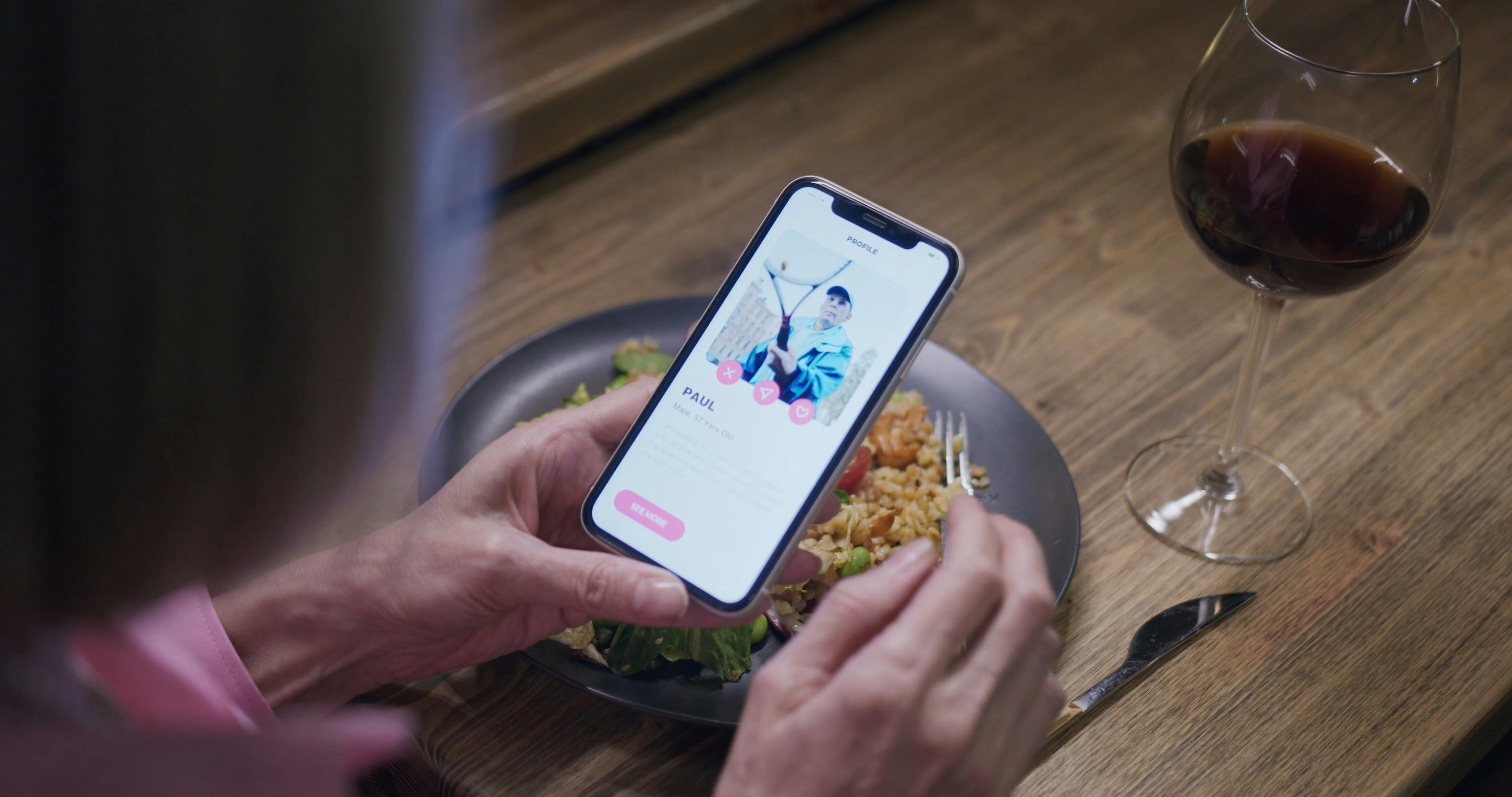 A Woman Scrolling Through Her Phone While at the Dinner Table Free ...