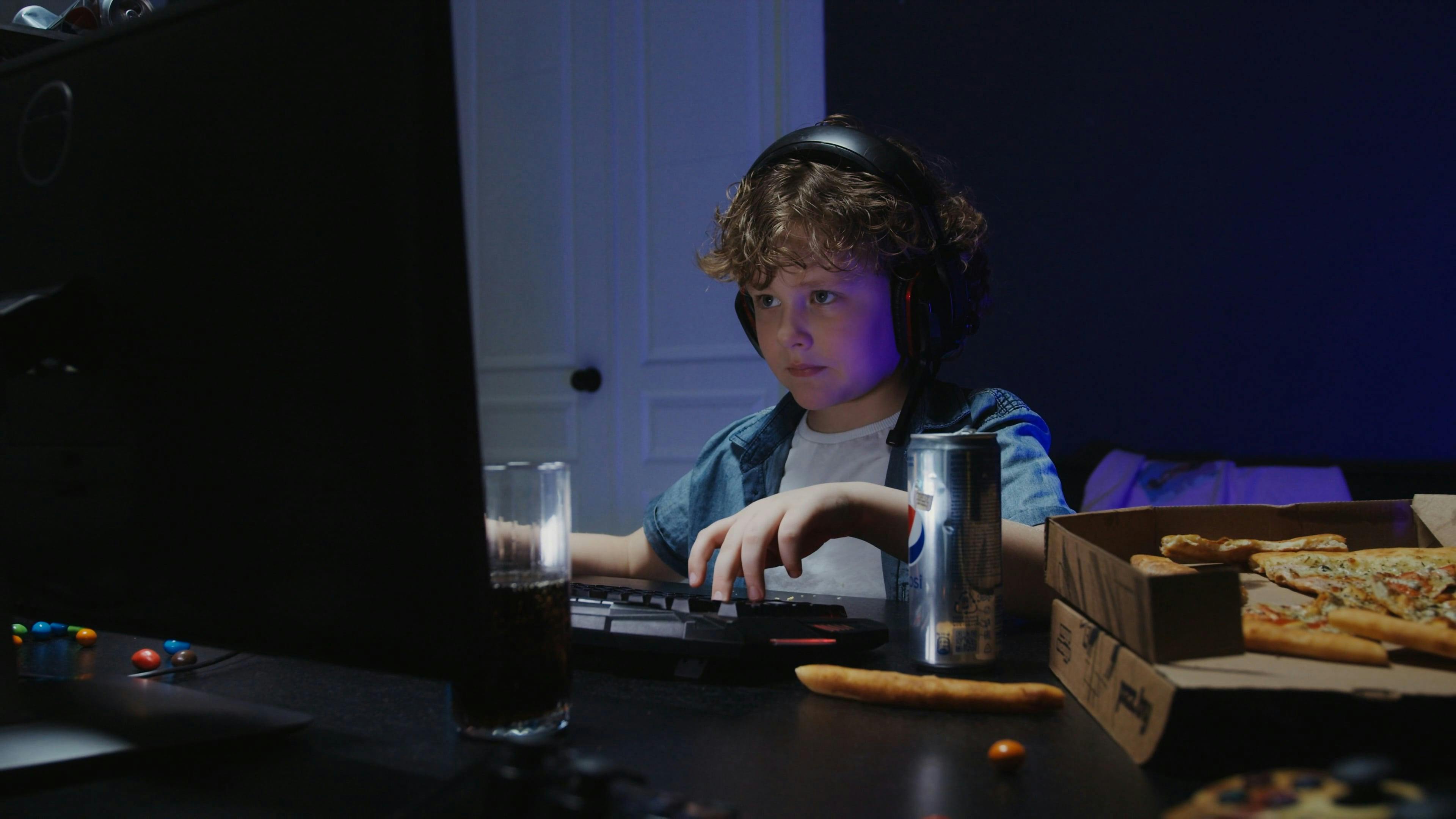A Boy Eating Chips and Drinking Soda While Using Computer Free Stock ...