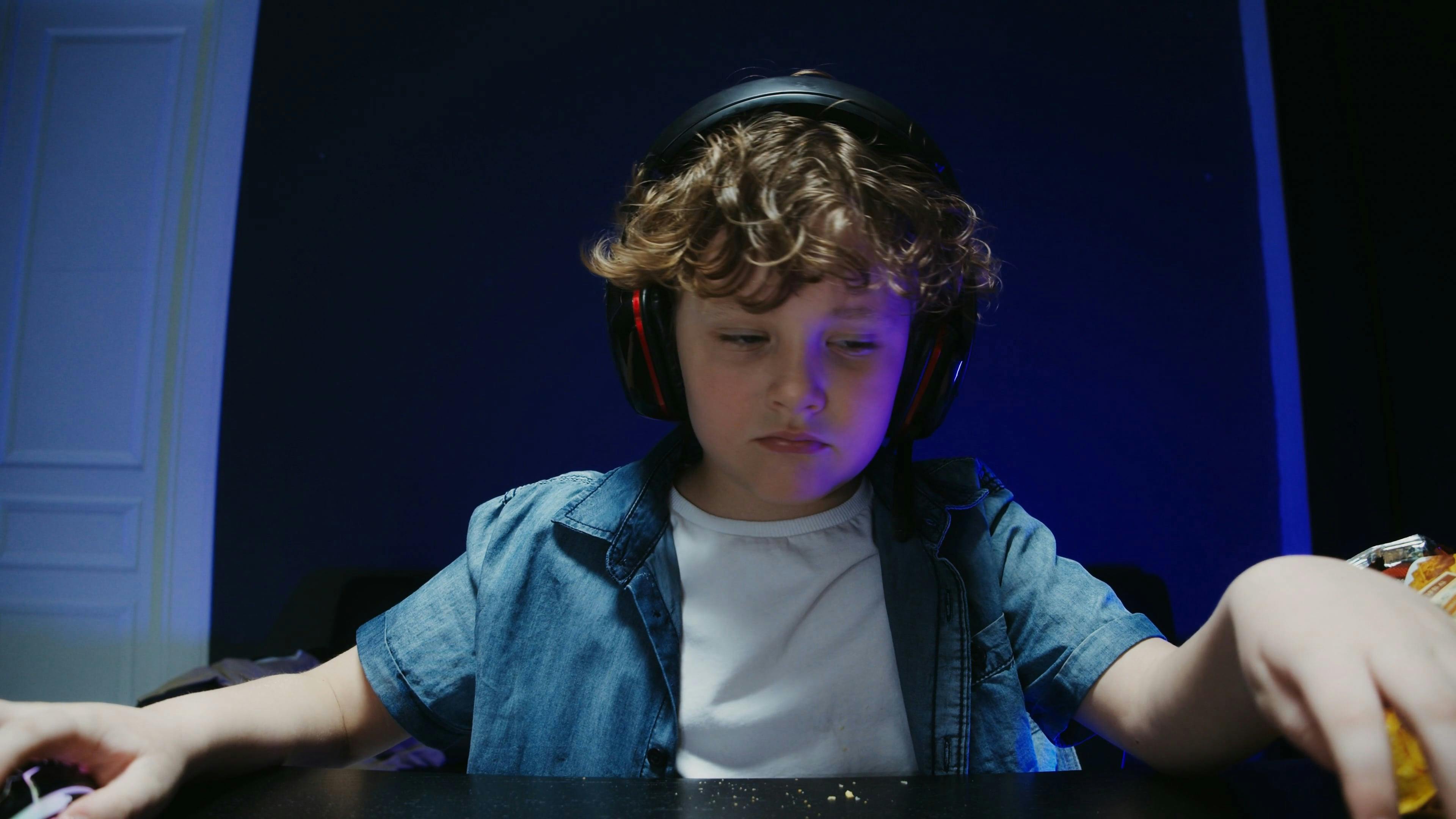 A Boy Playing a Computer Game While Eating Chips · Free Stock Video