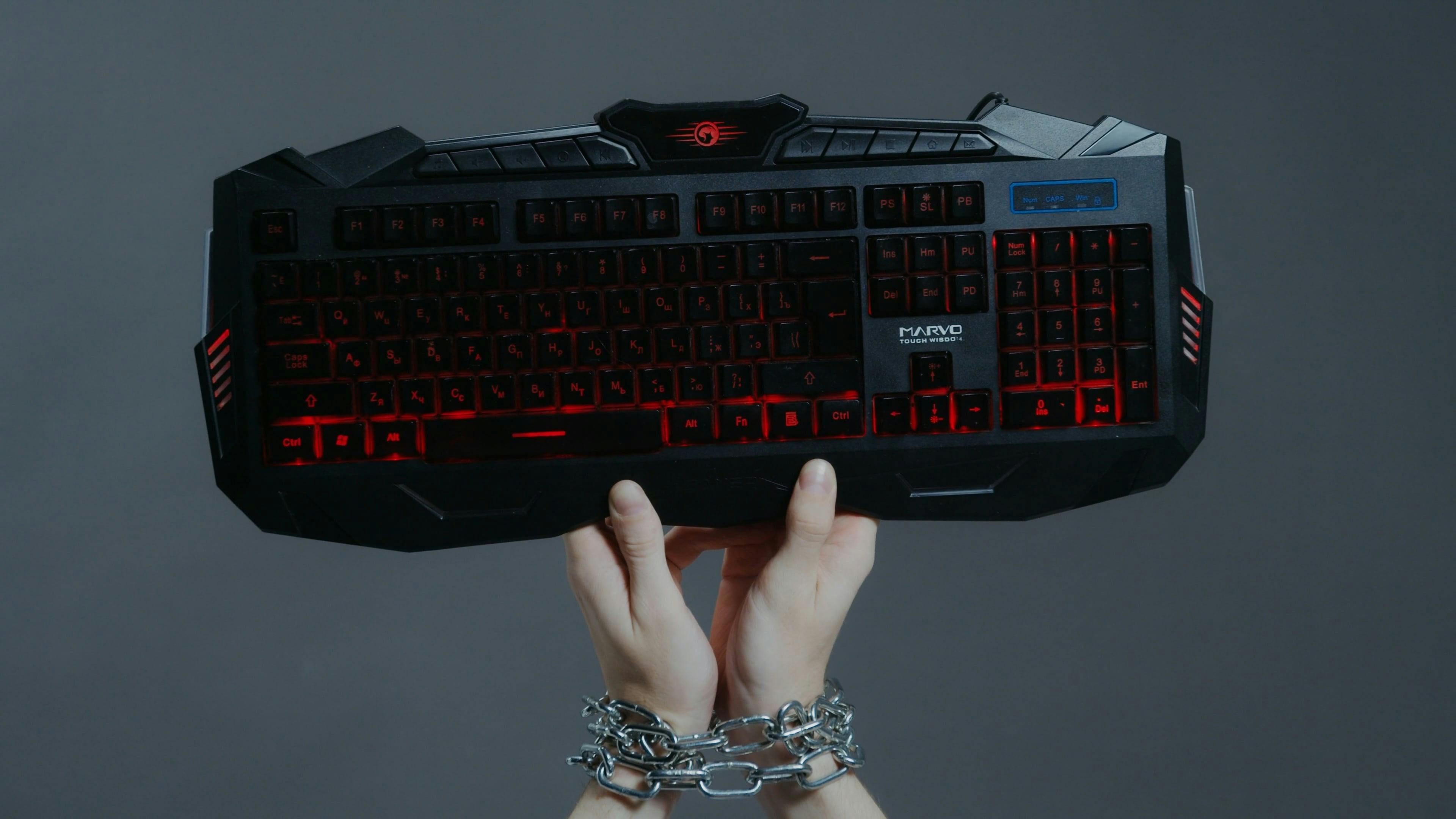 A Person Holding a Gaming Keyboard while Chained on the Wrist Free ...