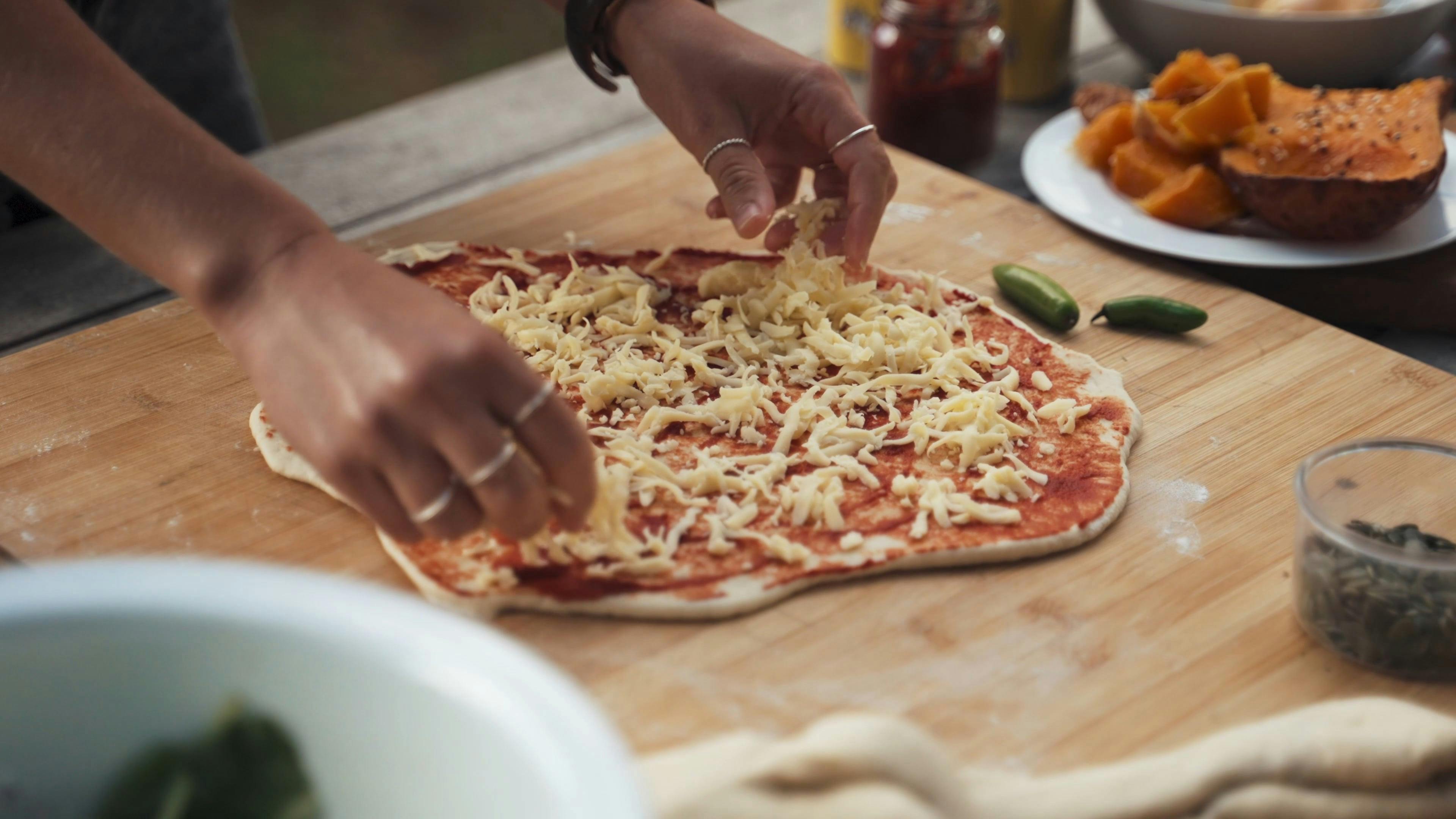 Person Putting Cheese on Pizza Dough · Free Stock Video