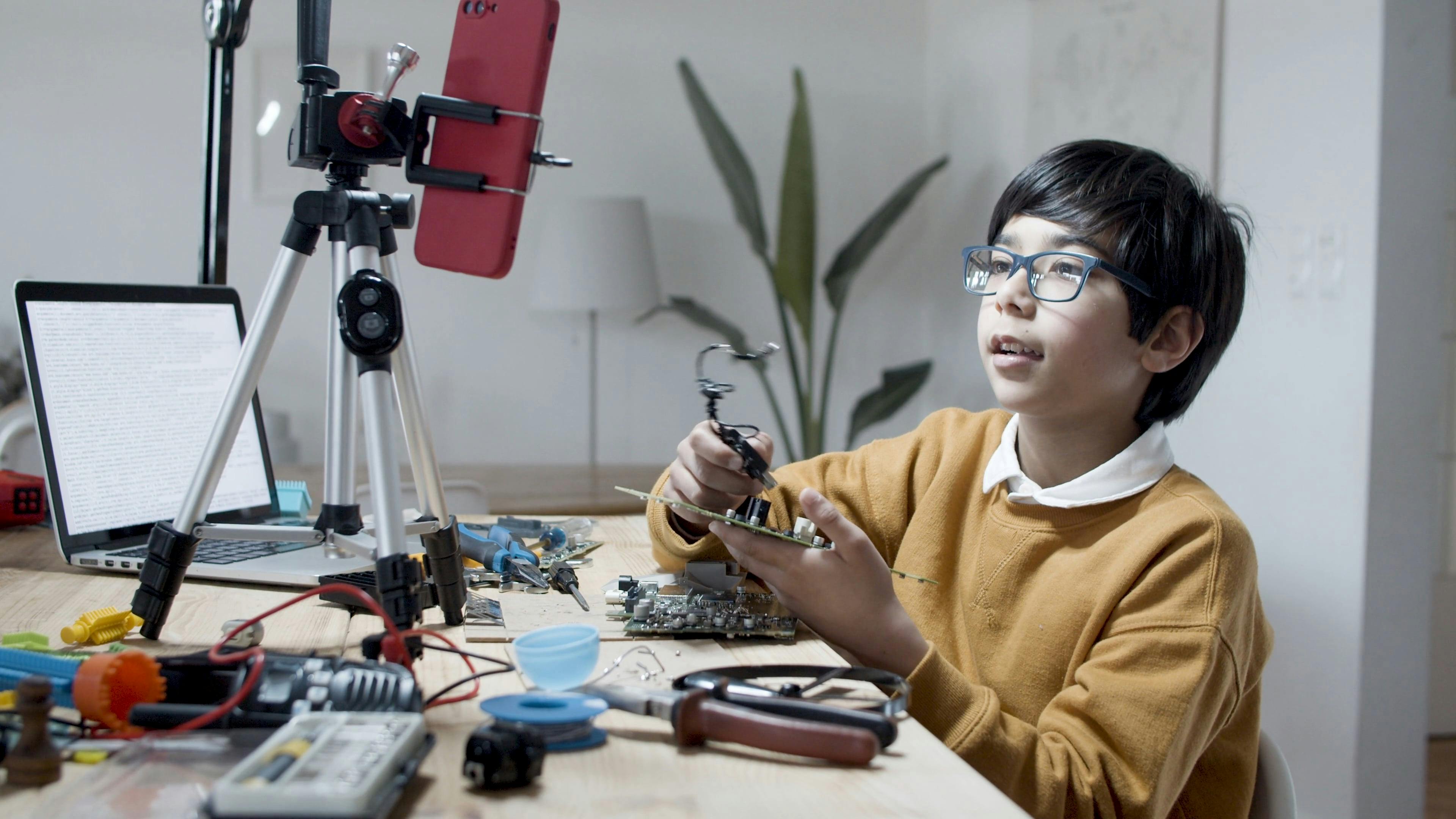 A Kid Having a Video Call on His Smartphone while Holding a Circuit ...