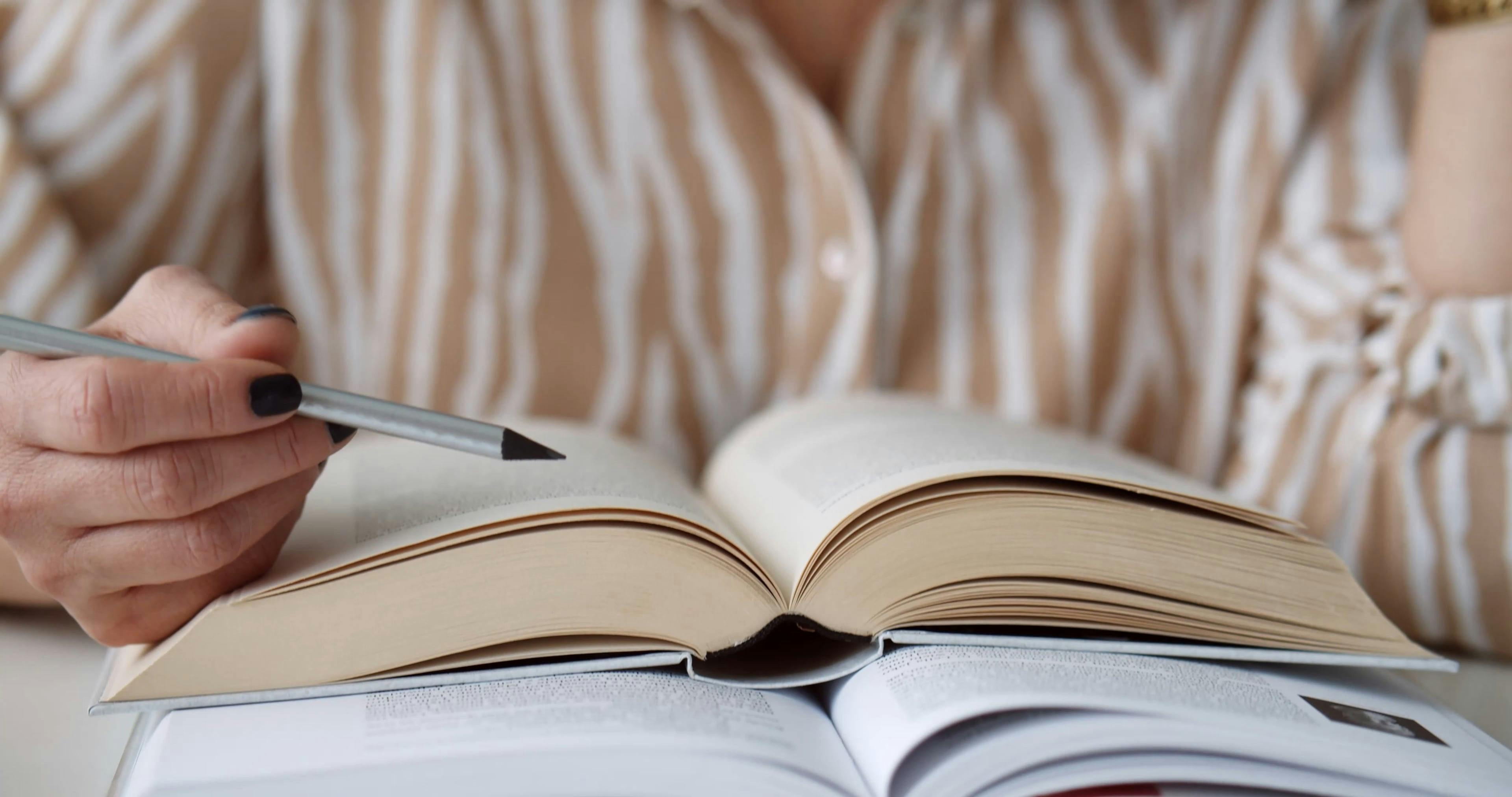 A Woman Reading while Holding a Pen · Free Stock Video