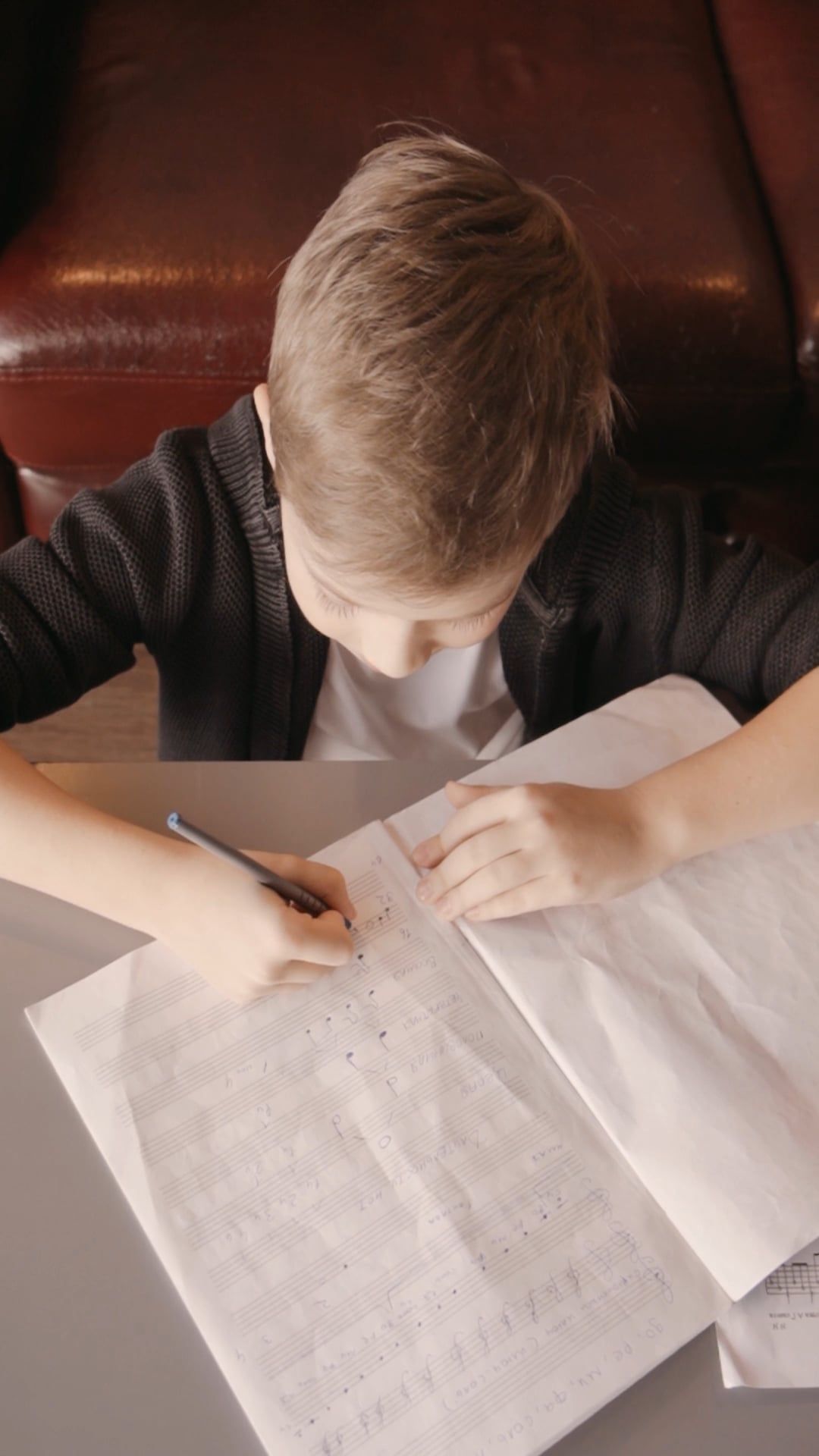A Child Using A Pencil Writing On A Paper Inside A Classroom · Free ...