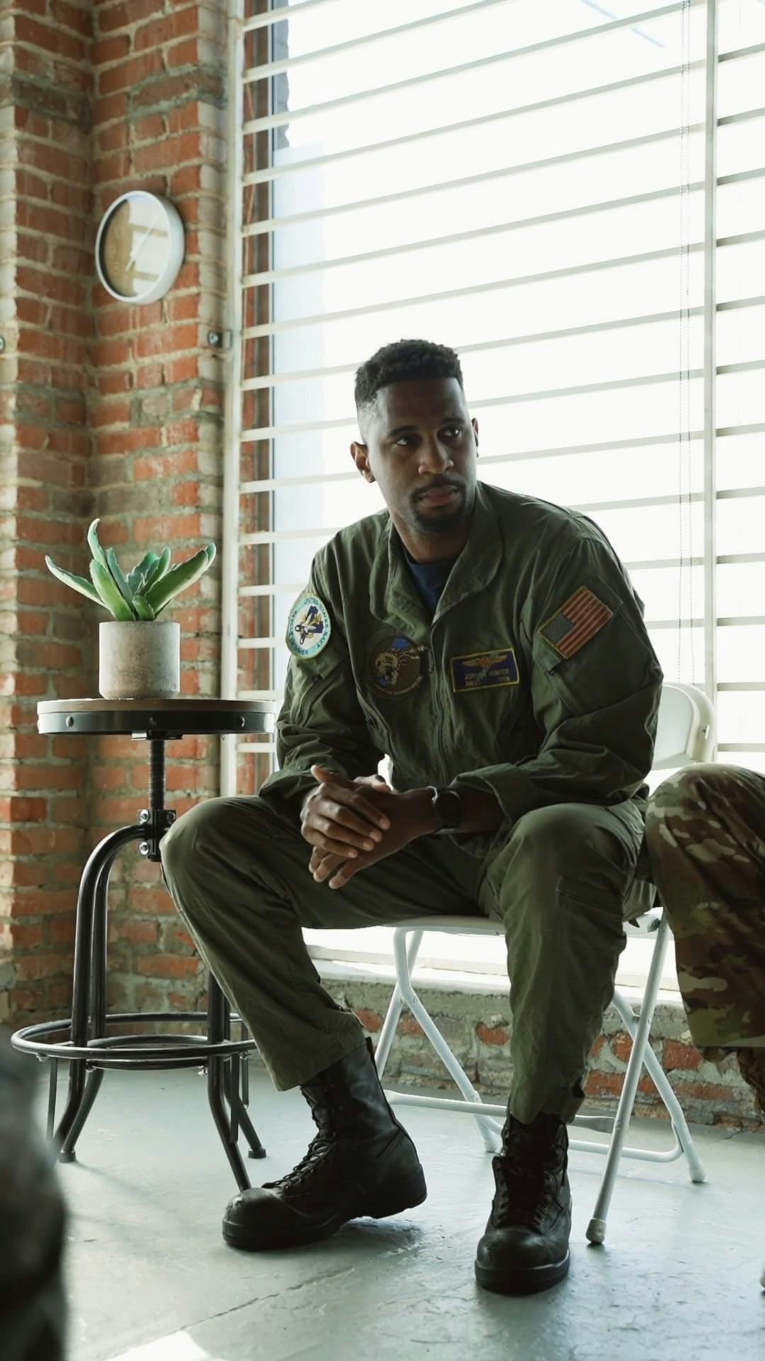 A Army Person on Camouflage Unifom Sitting on a Chair while Holding ...