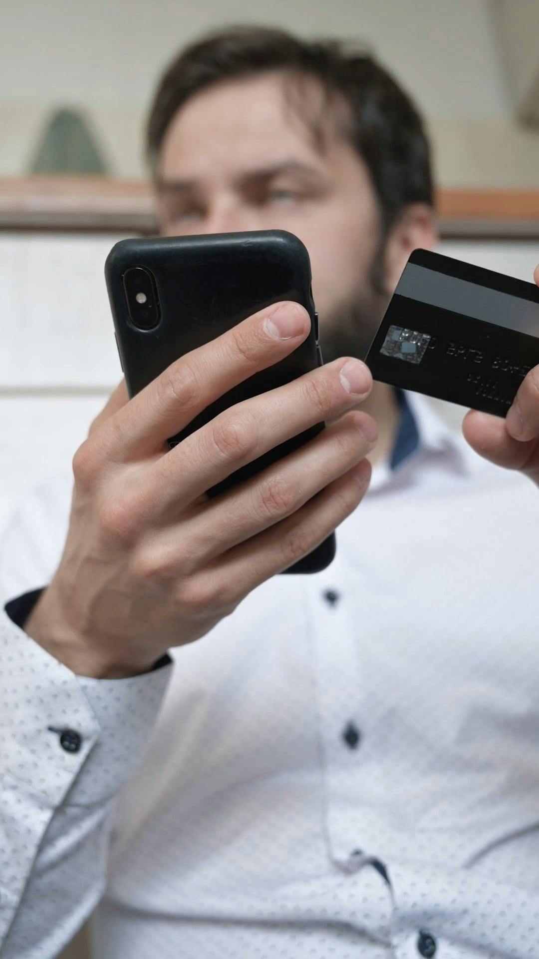 A Man Using a Smartphone while Holding a Bank Card · Free Stock Video