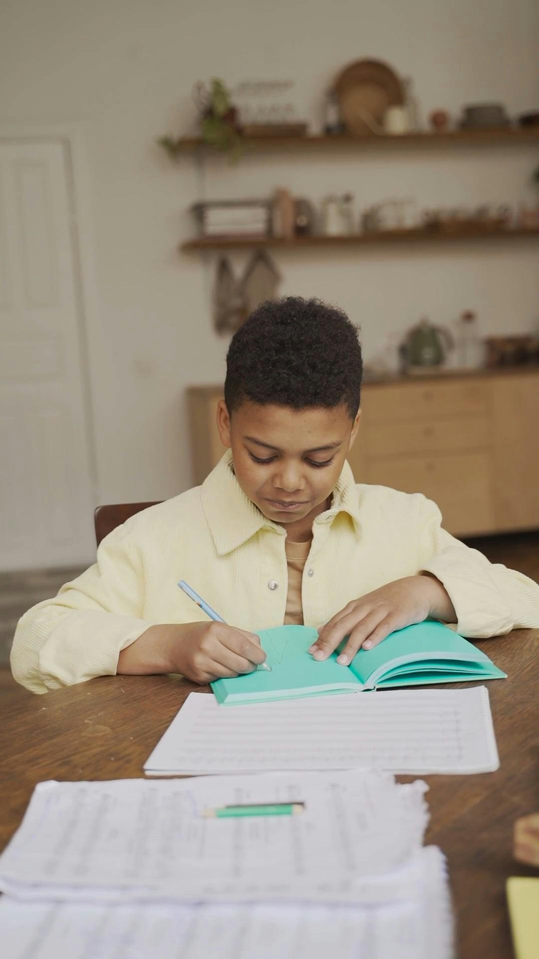 A Child Using A Pencil Writing On A Paper Inside A Classroom · Free ...