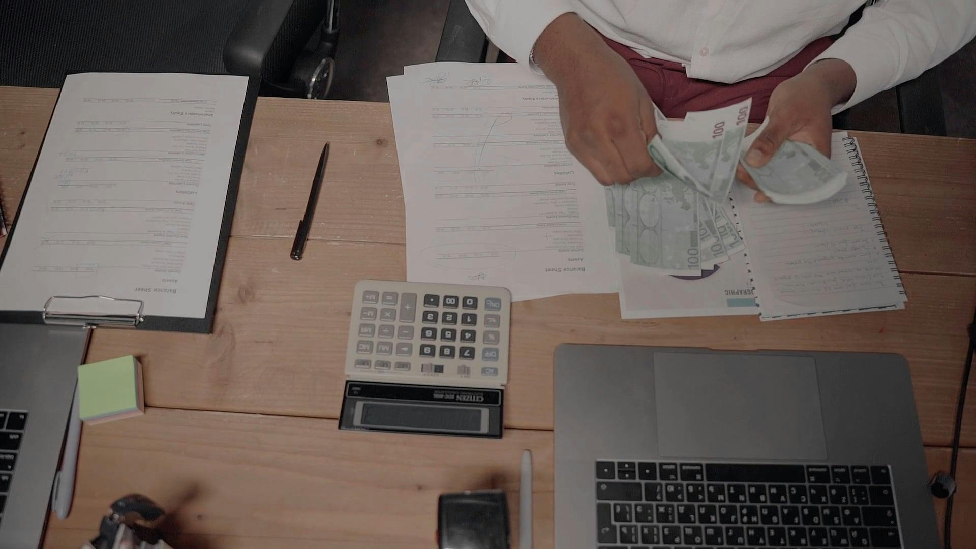 A Person Counting and Computing Money While Writing on a Notepad Free ...