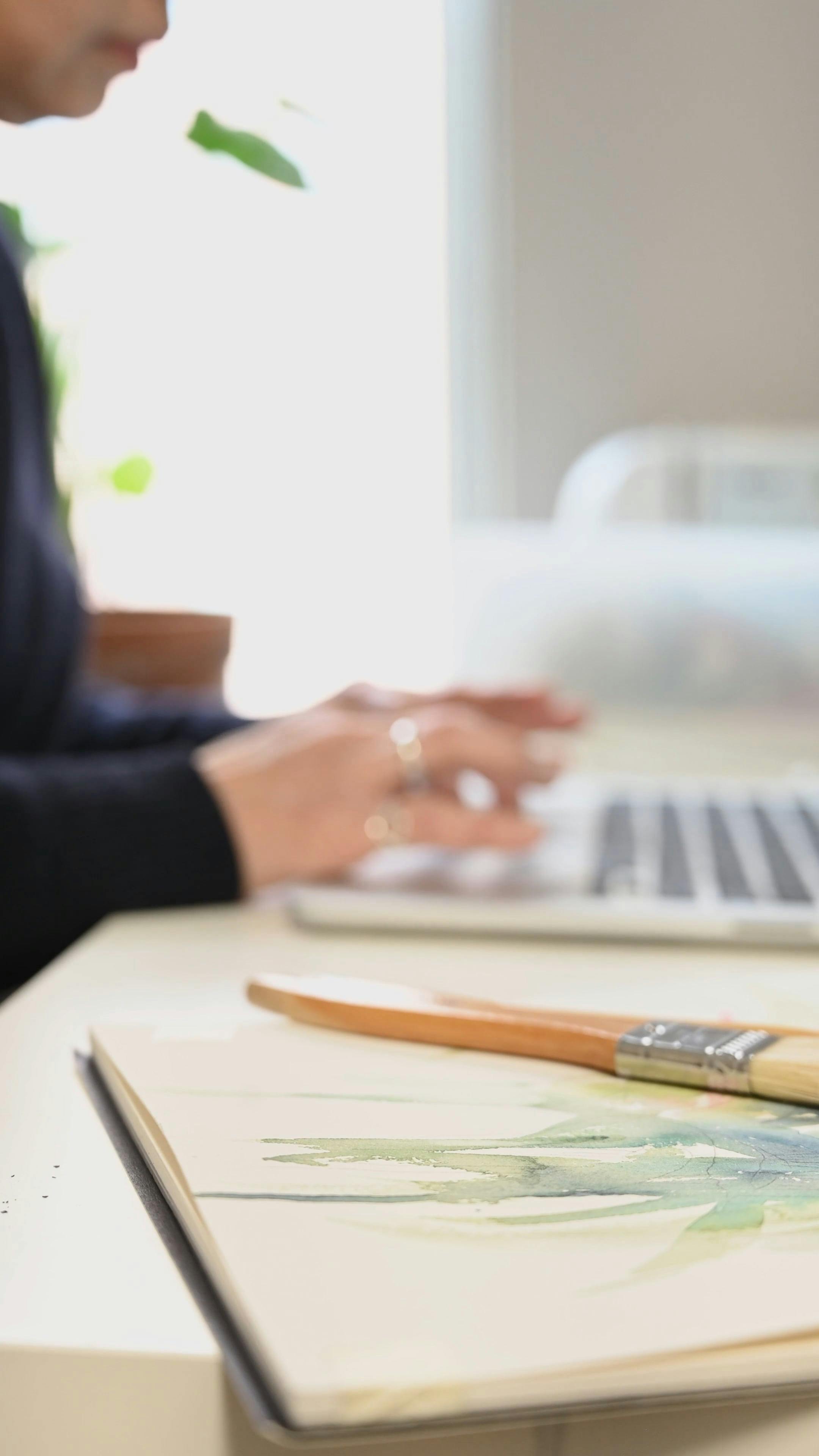 Person Typing on Notebook Beside Canvas and Paintbrush Free Stock Video ...