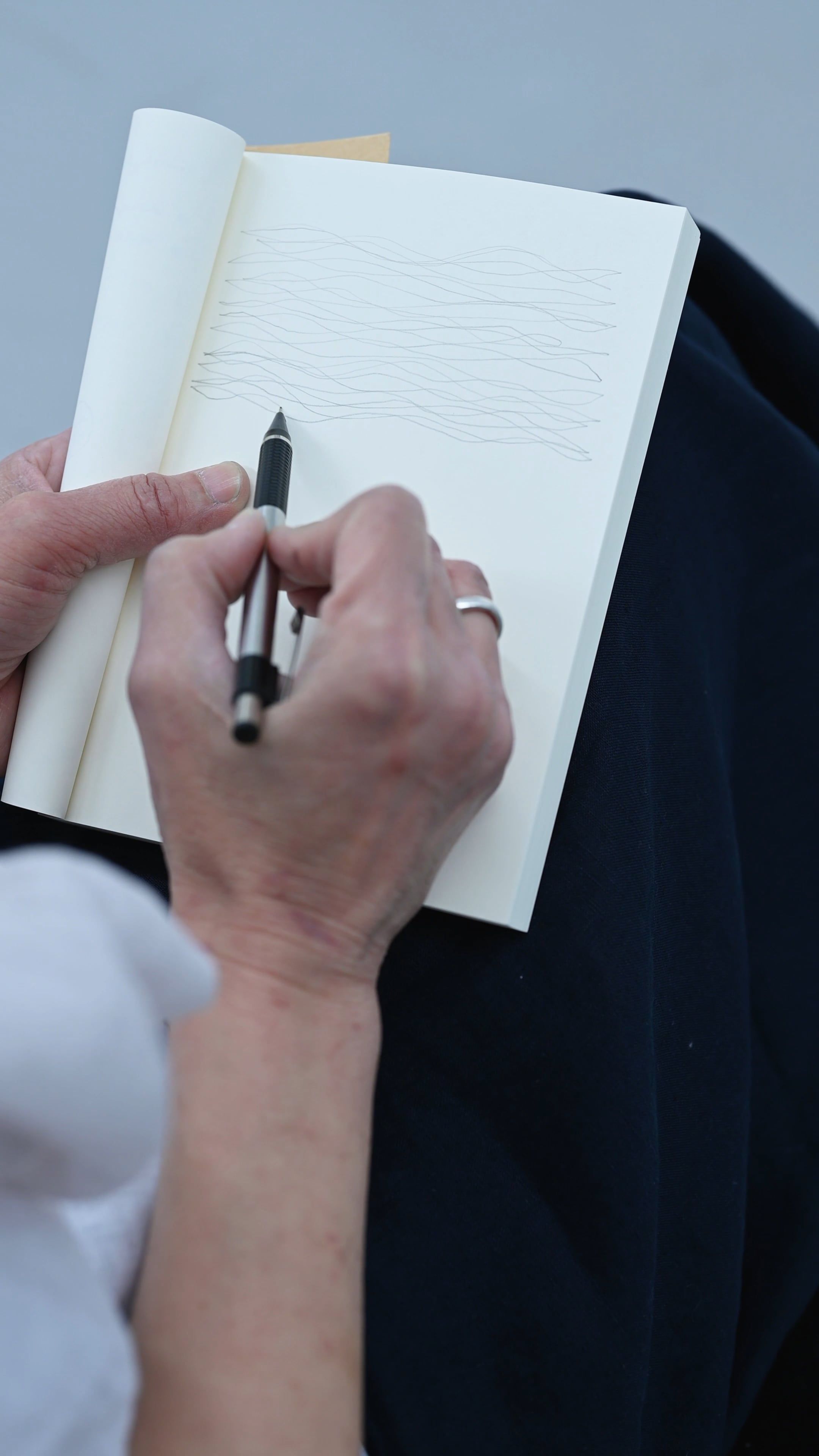 A Person Drawing Wavy Lines on a Notebook · Free Stock Video