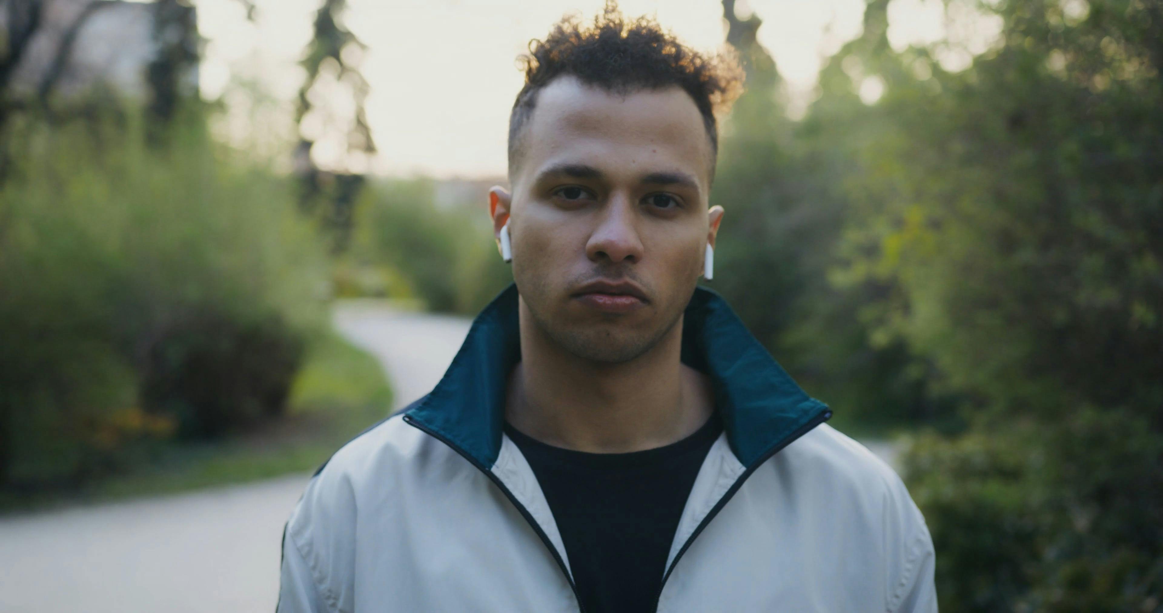 A Man Wearing Earbuds is Looking at the Camera · Free Stock Video