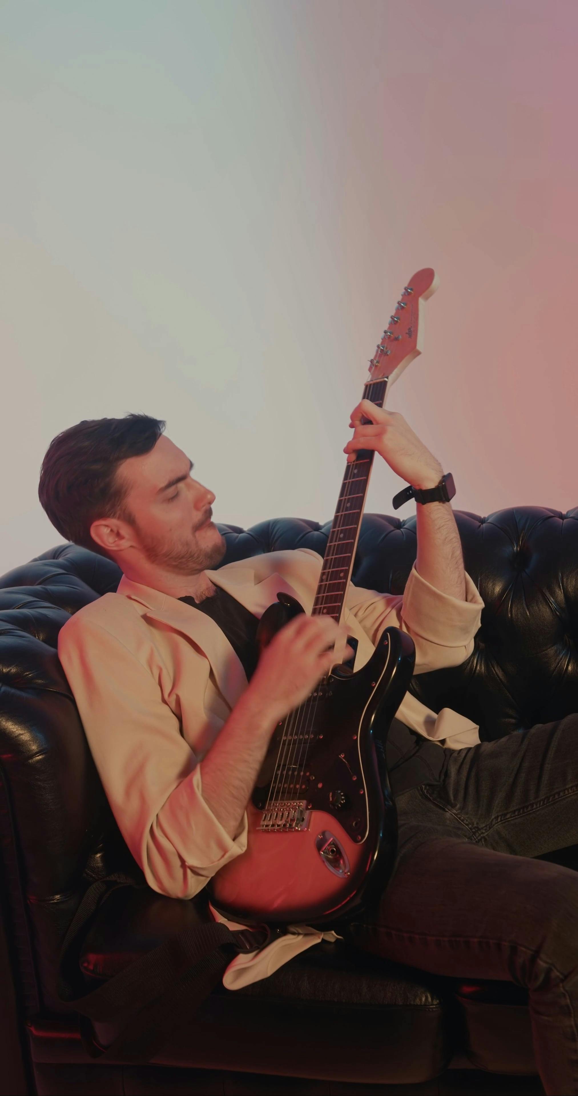 A Man Playing Guitar while Looking at the Musical Notes · Free Stock Video
