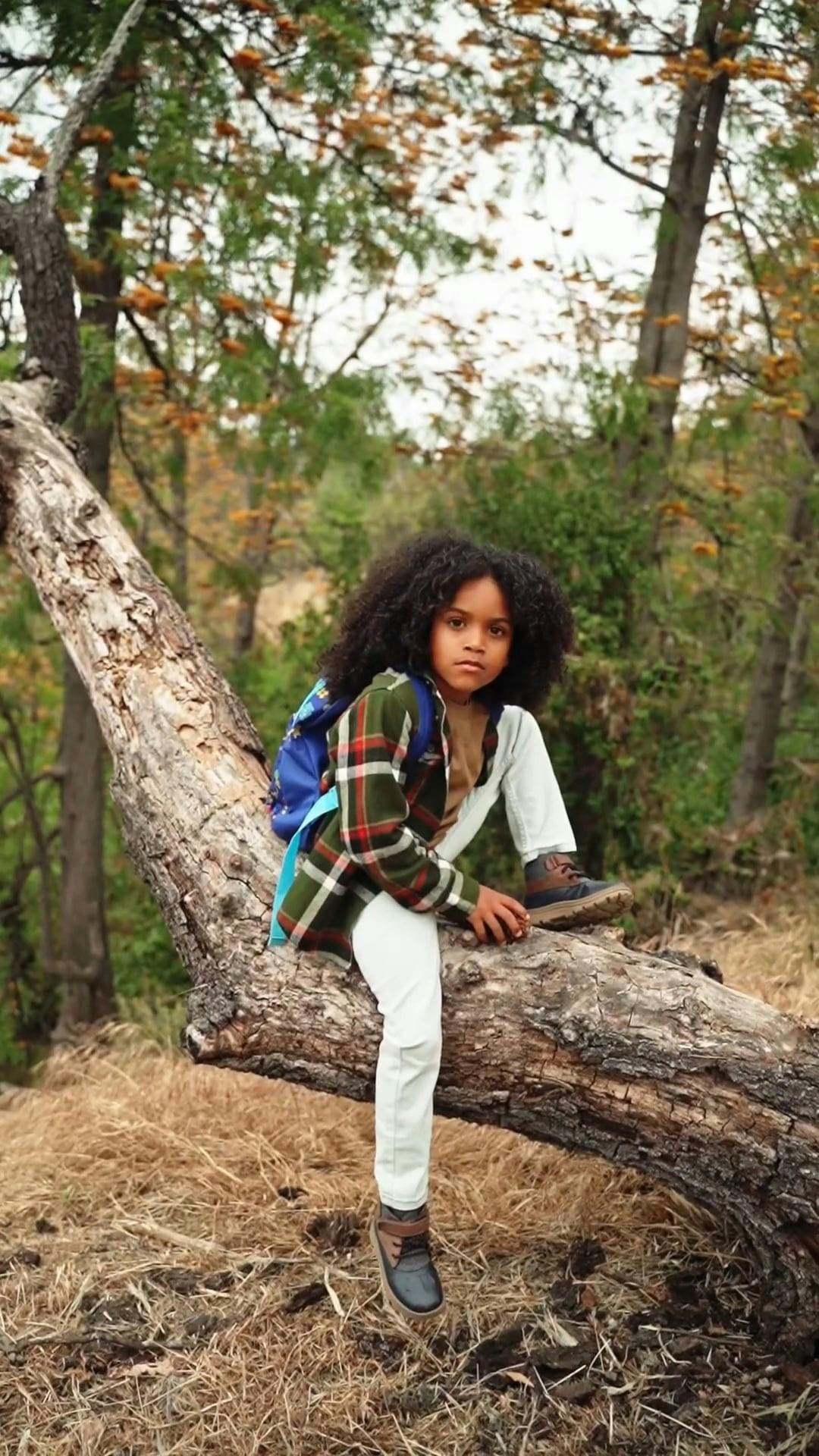 A Child Sitting on a Tree Trunk Smiling and Looking at Camera · Free ...