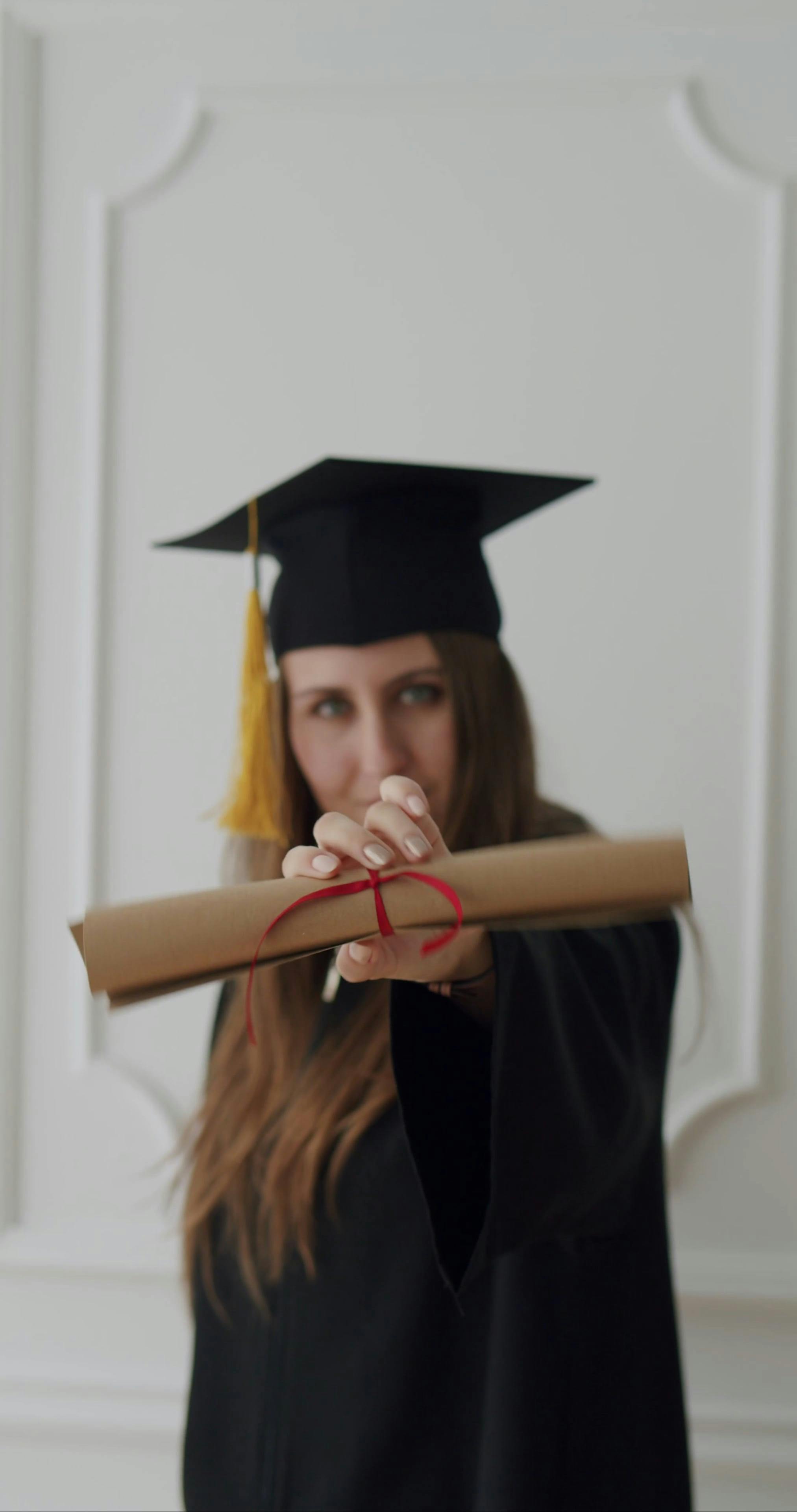 A Woman Wearing a Graduation Gown Holding a Graduation Cap and a ...