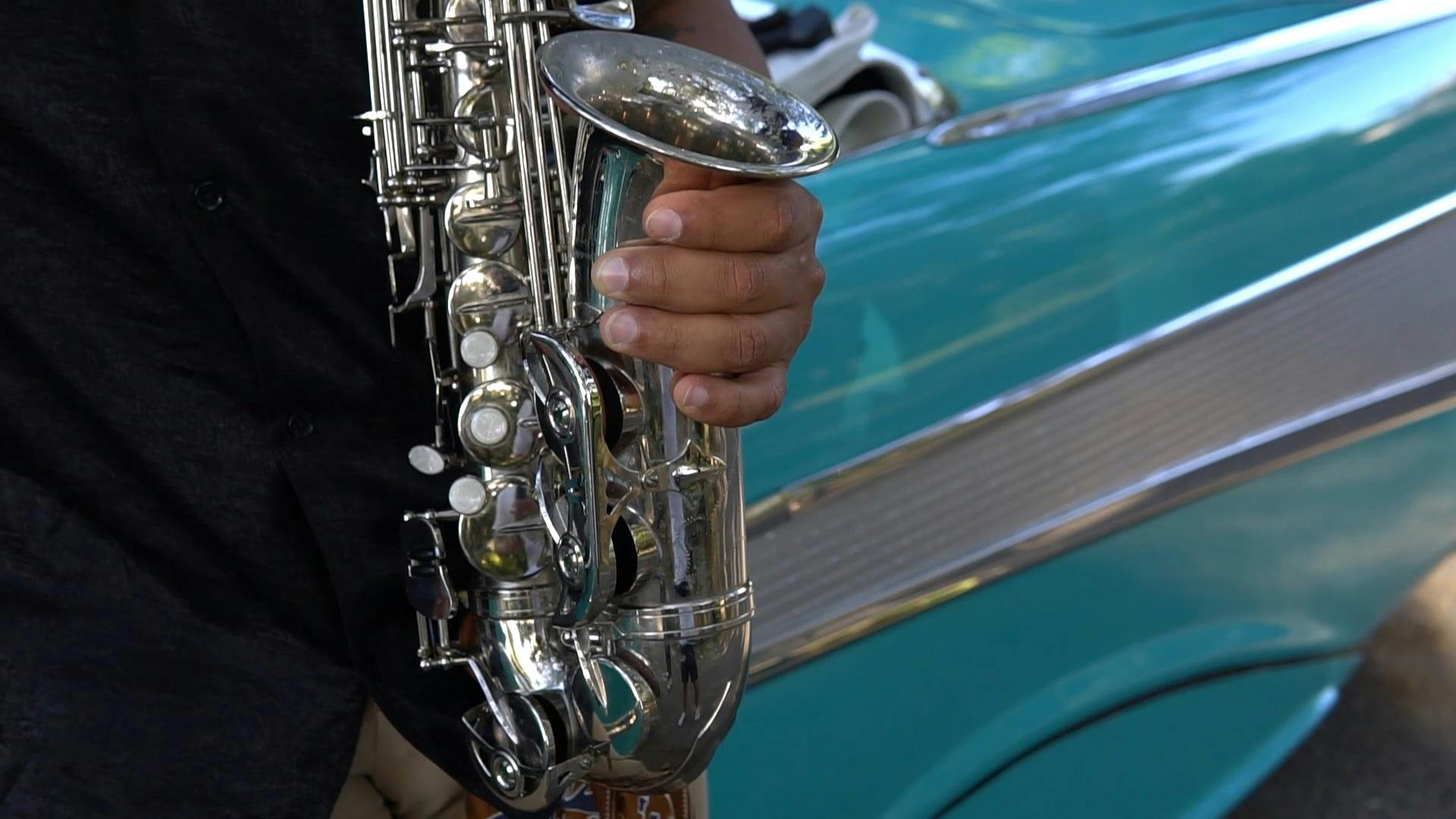 A Man Holding a Saxophone beside a Car · Free Stock Video