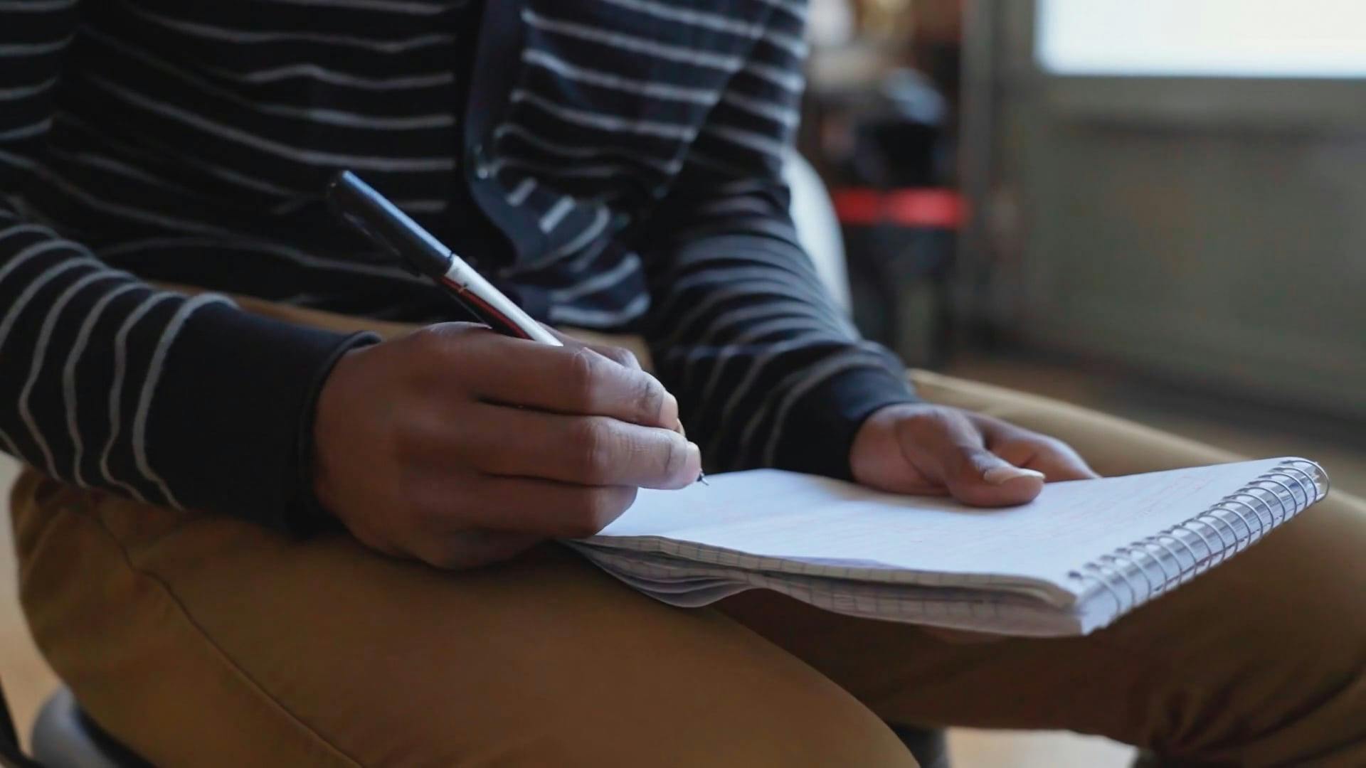 Person Writing on a Notepad · Free Stock Video
