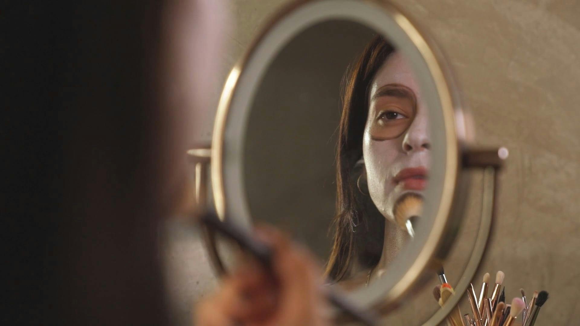 A Reflection of a Woman in the Mirror Applying Makeup with a Makeup ...