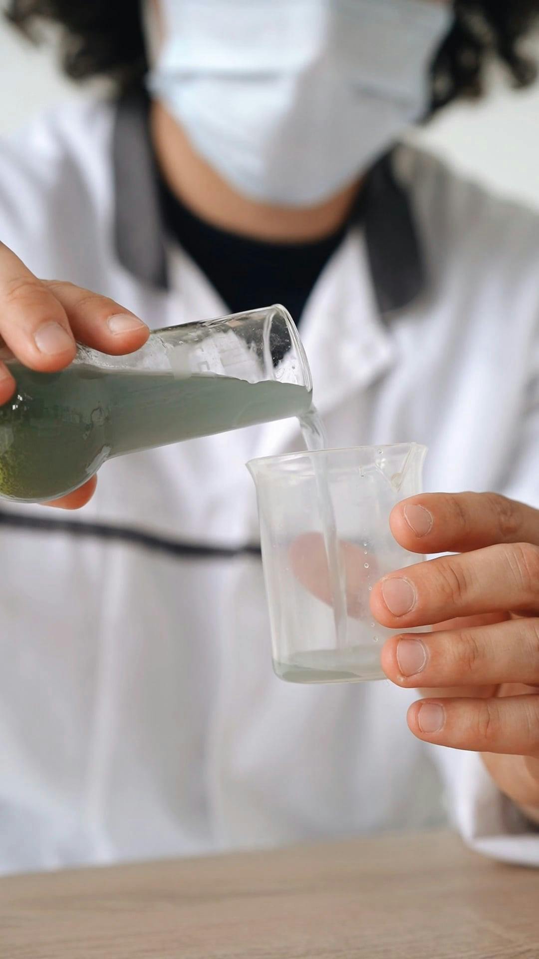 A Person in a Face Mask Pouring Liquid in a Beaker Free Stock Video ...