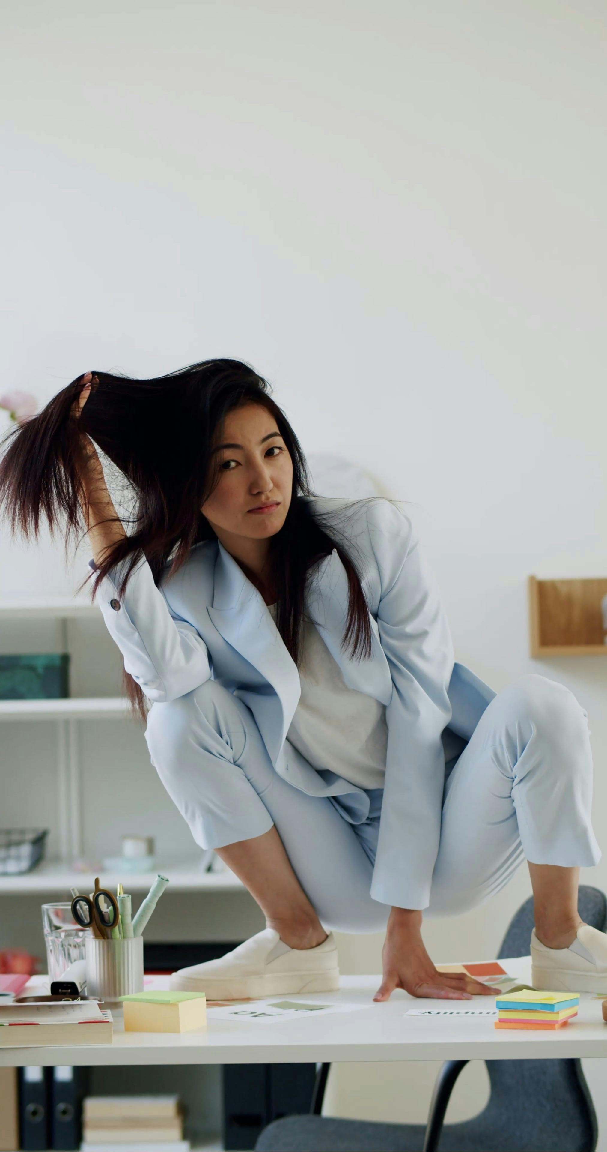 A Woman Squatting on top of a Table at an Office · Free Stock Video