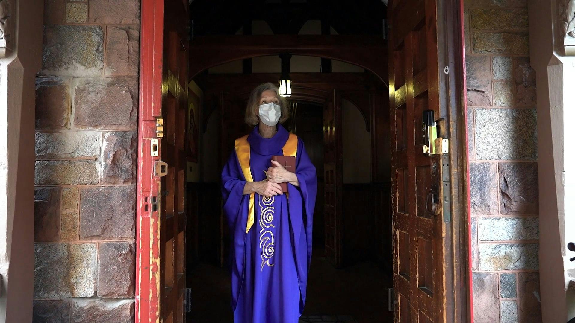 Woman Pastor Wearing Face Mask and Purple Robe Standing On Doorway Of ...