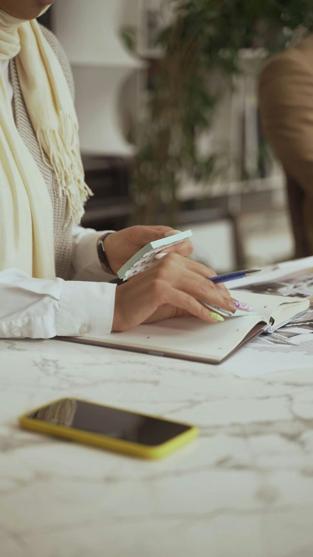 A Woman Writing on a Notebook While Having a Phone Call · Free Stock Video
