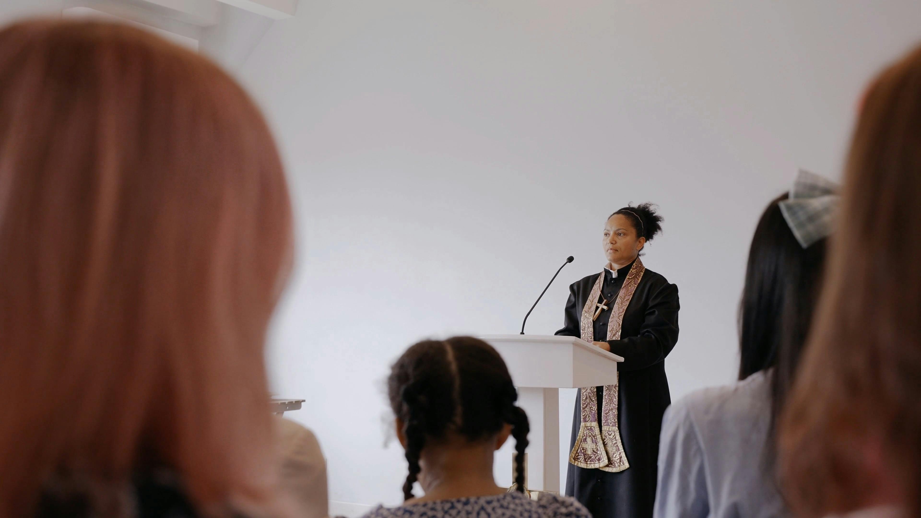 A Woman Pastor Holding a Bible while Talking In Front of the ...