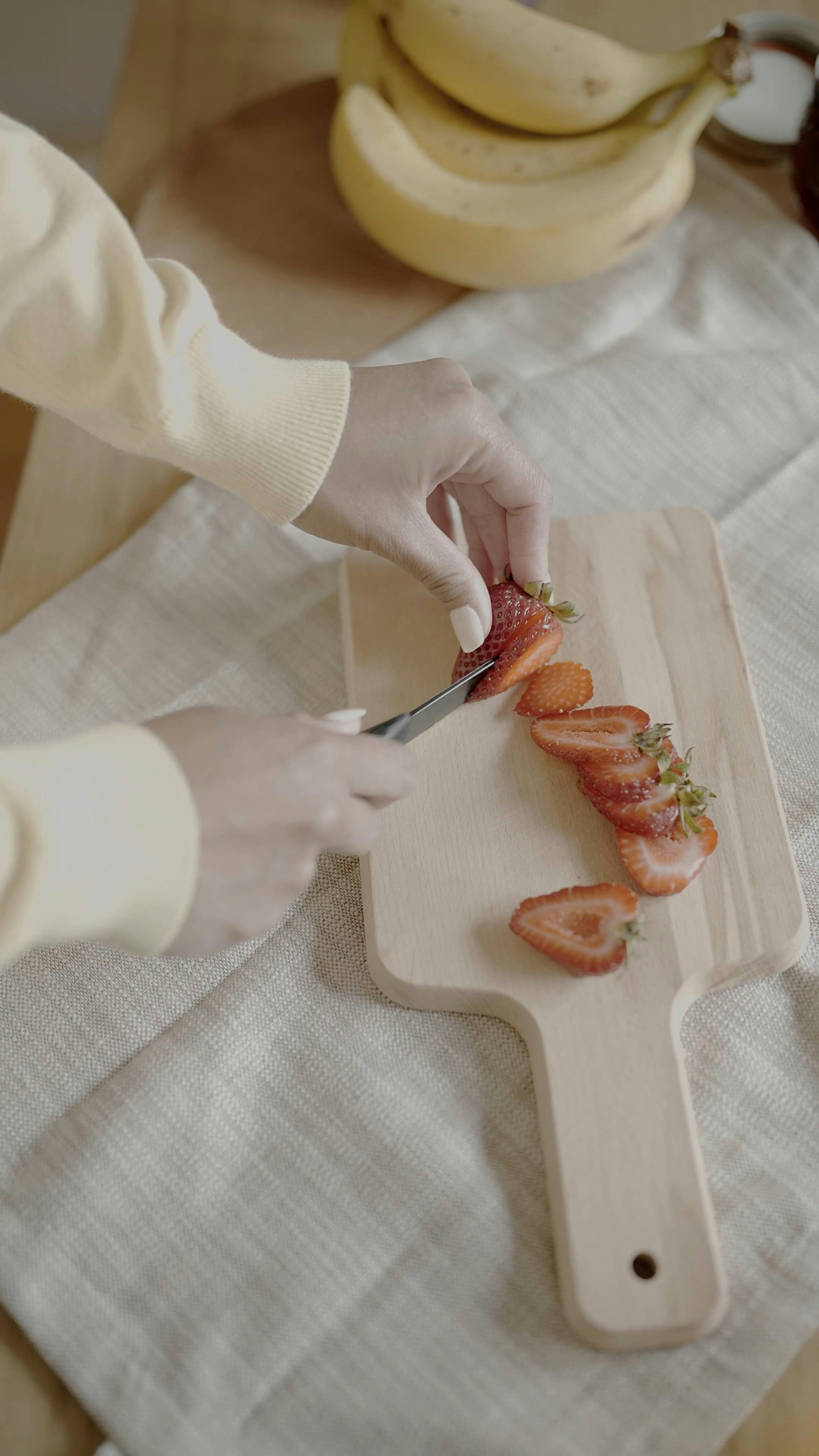 A Person Cutting Strawberries on a Wooden Chopping Board Free Stock ...