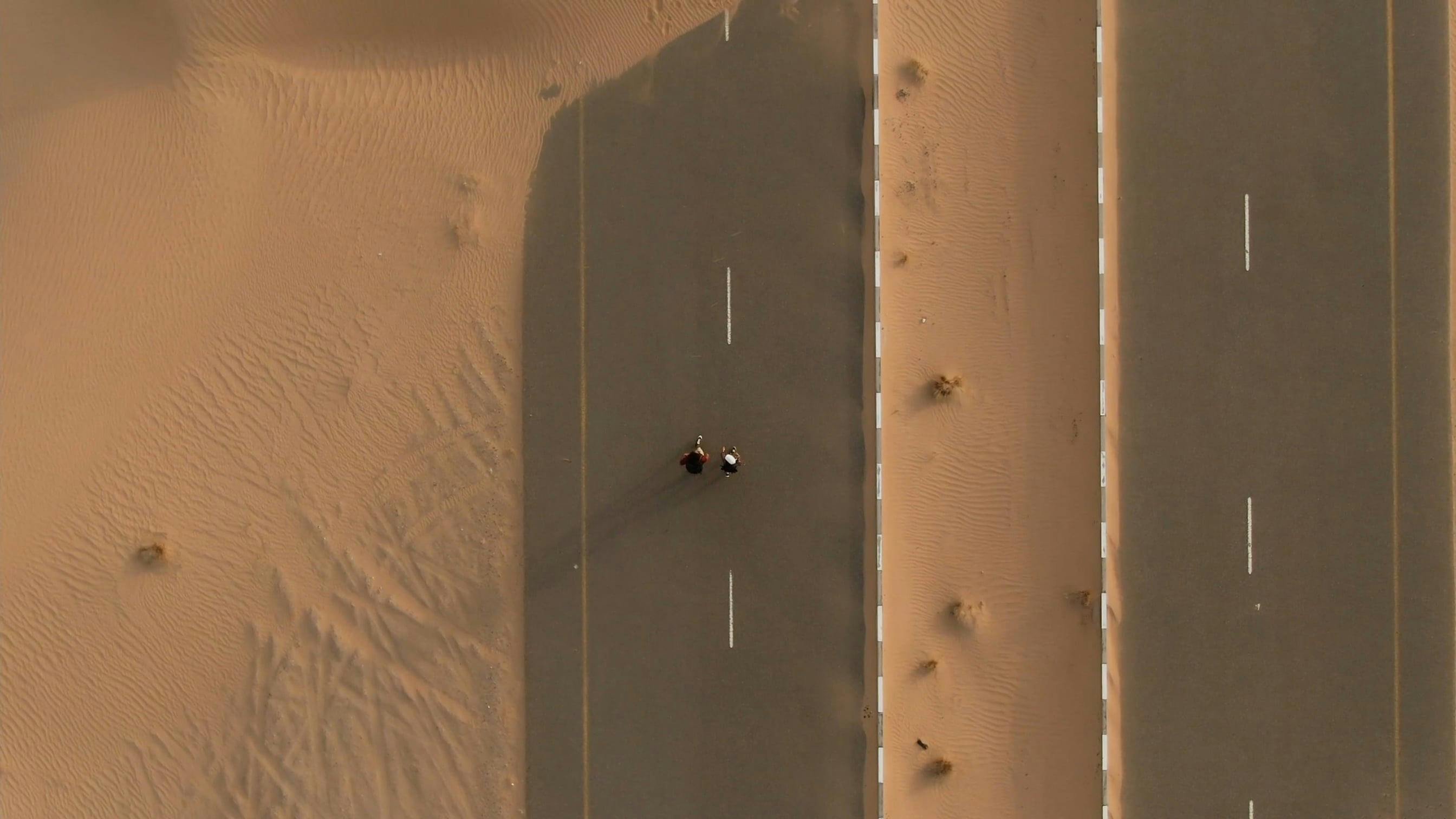 Drone Footage of Two Backpackers Walking on a Desert Road Free Stock ...