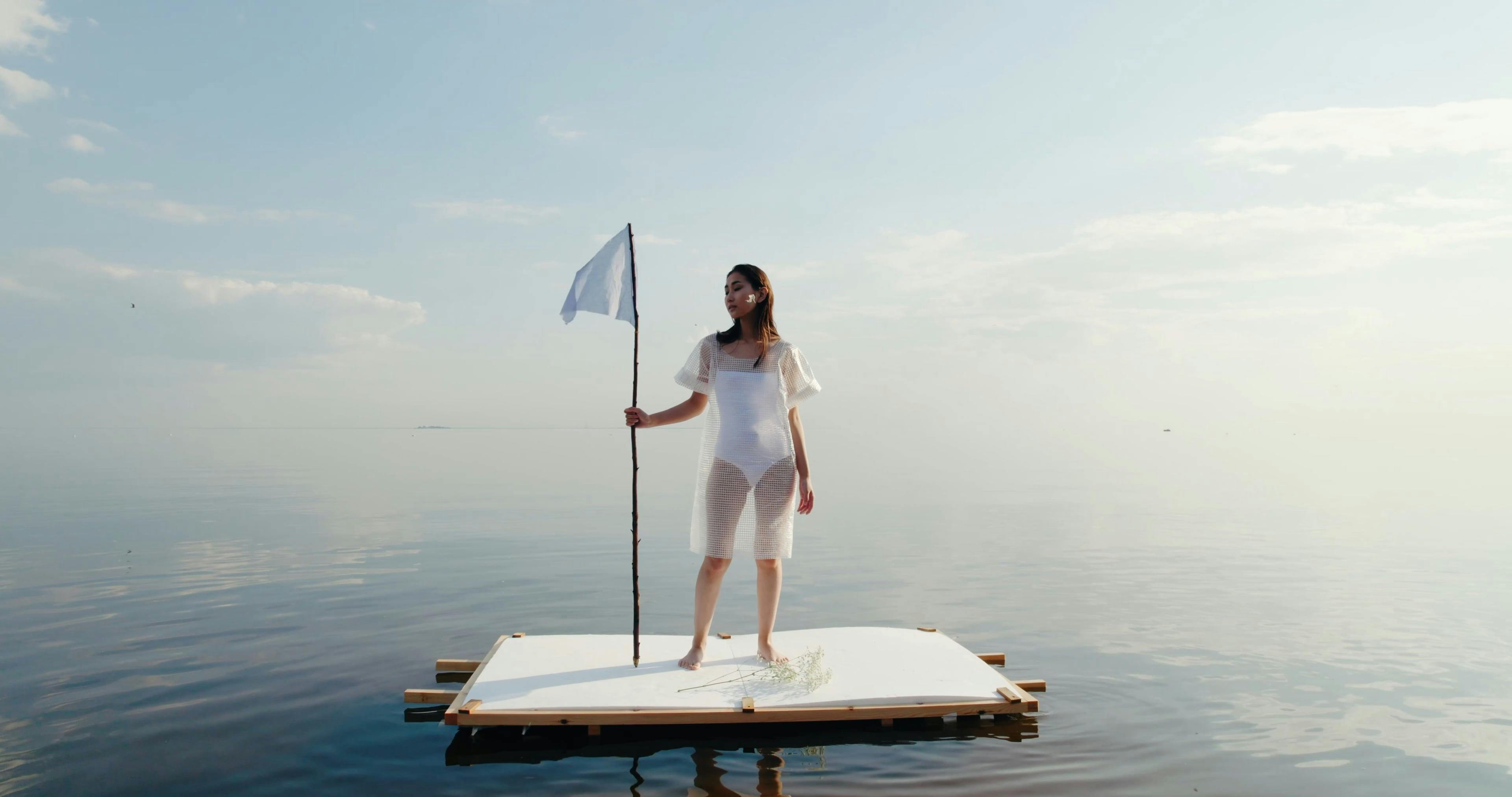 A Woman Holding a White Flag while Standing on the Raft Free Stock ...