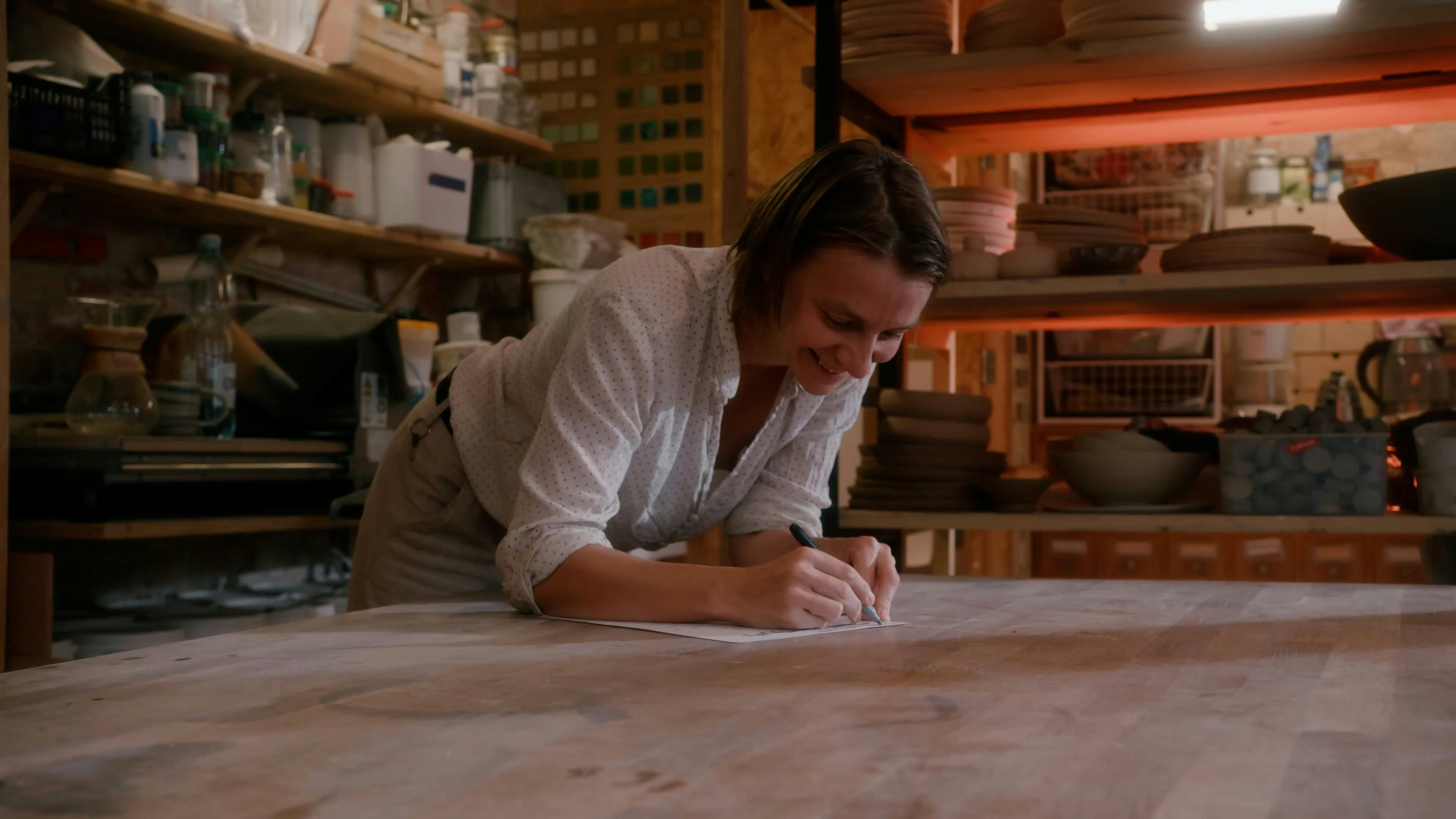 A Woman Smiling while Writing on the Table Free Stock Video Footage ...