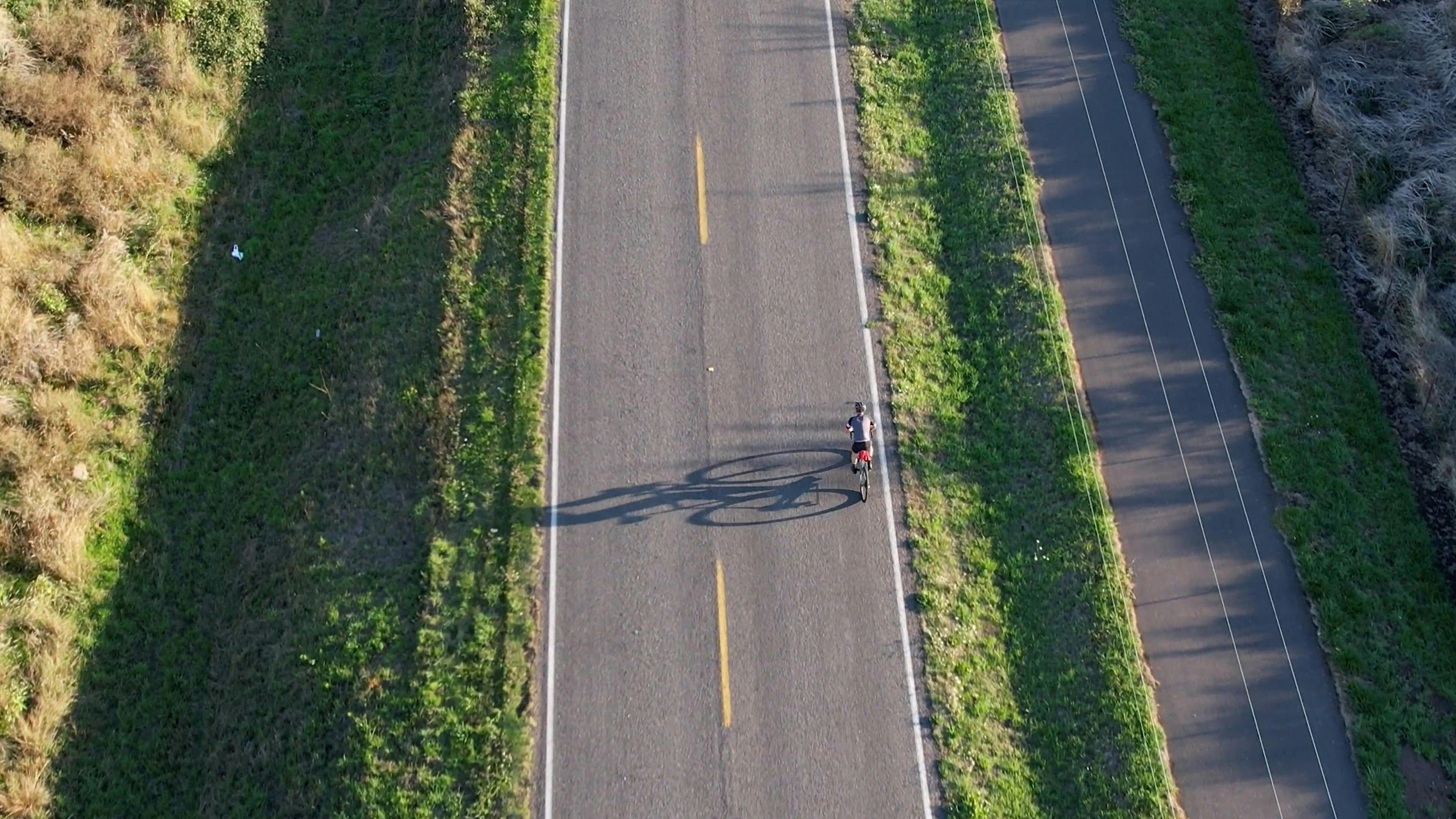 Drone following cyclist riding along straight road Free Stock Video ...