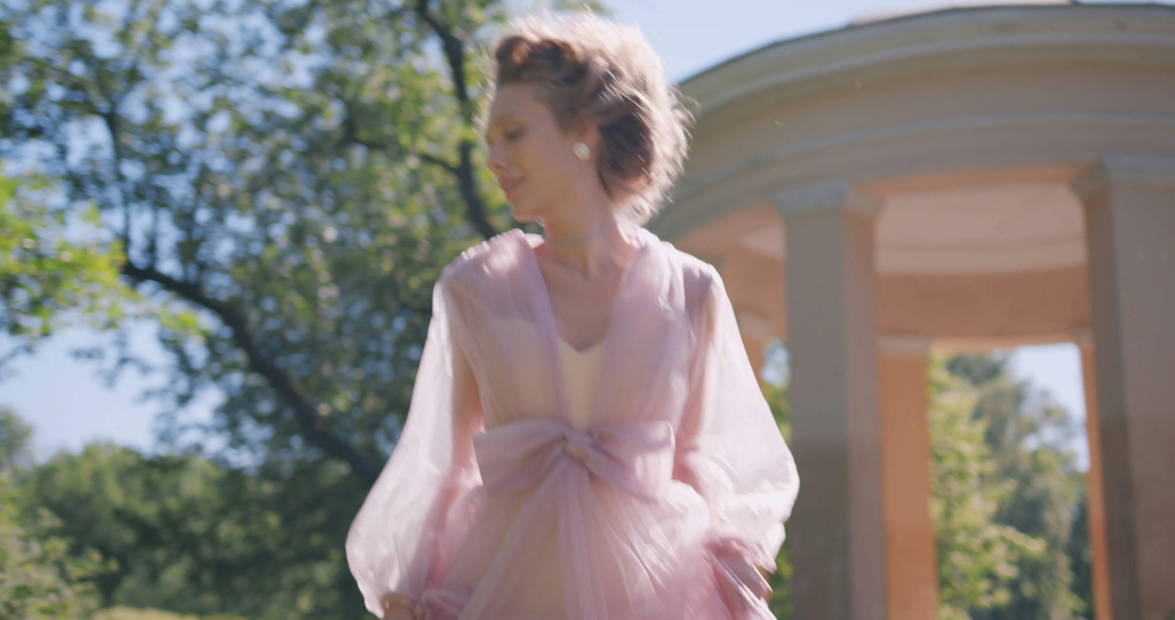 A Fashionable Woman in a Pink Dress Running in a Garden Free Stock ...